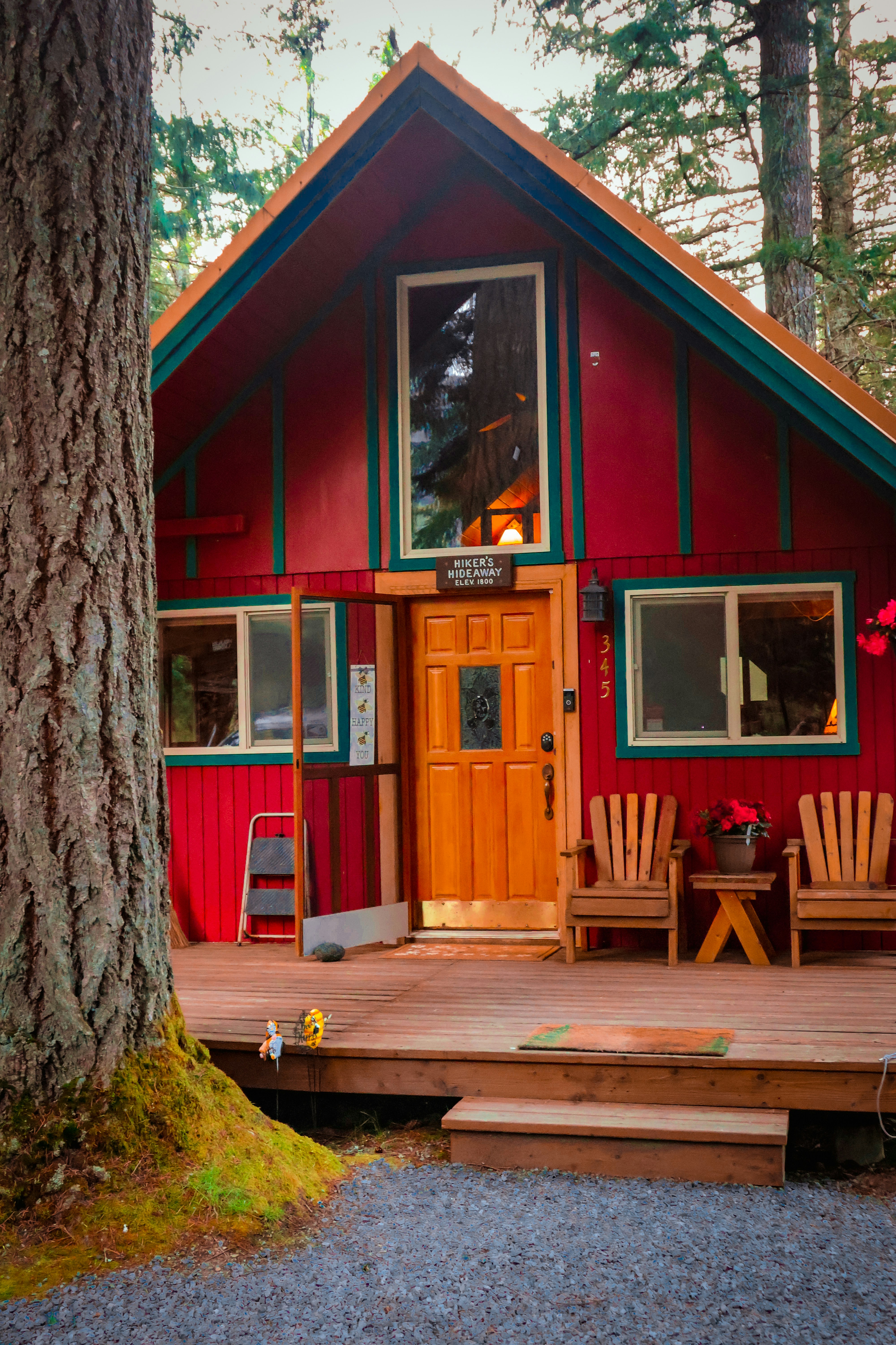 Cozy red cabin with a wooden porch in a forest.