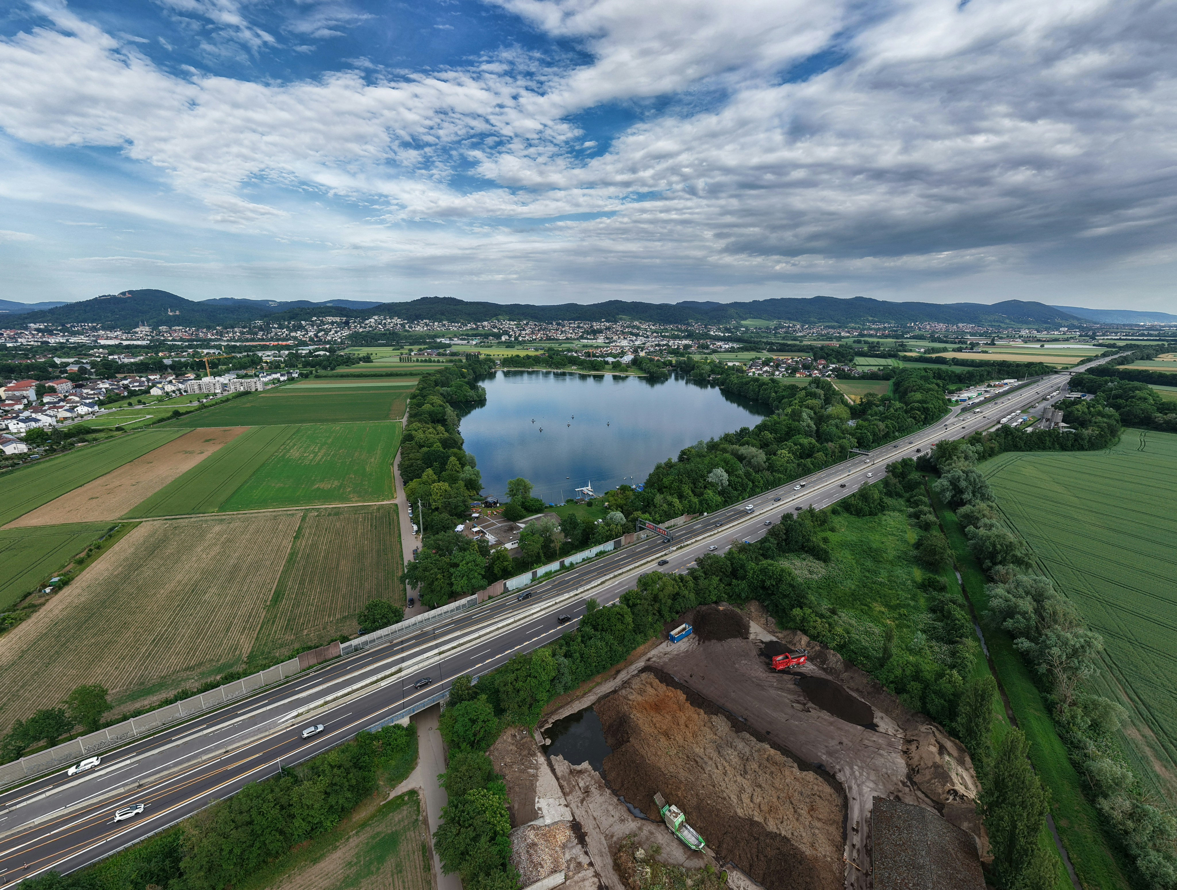Aerial Crossroads: Highway, Pond, and Quarry in Verdant Lowlands