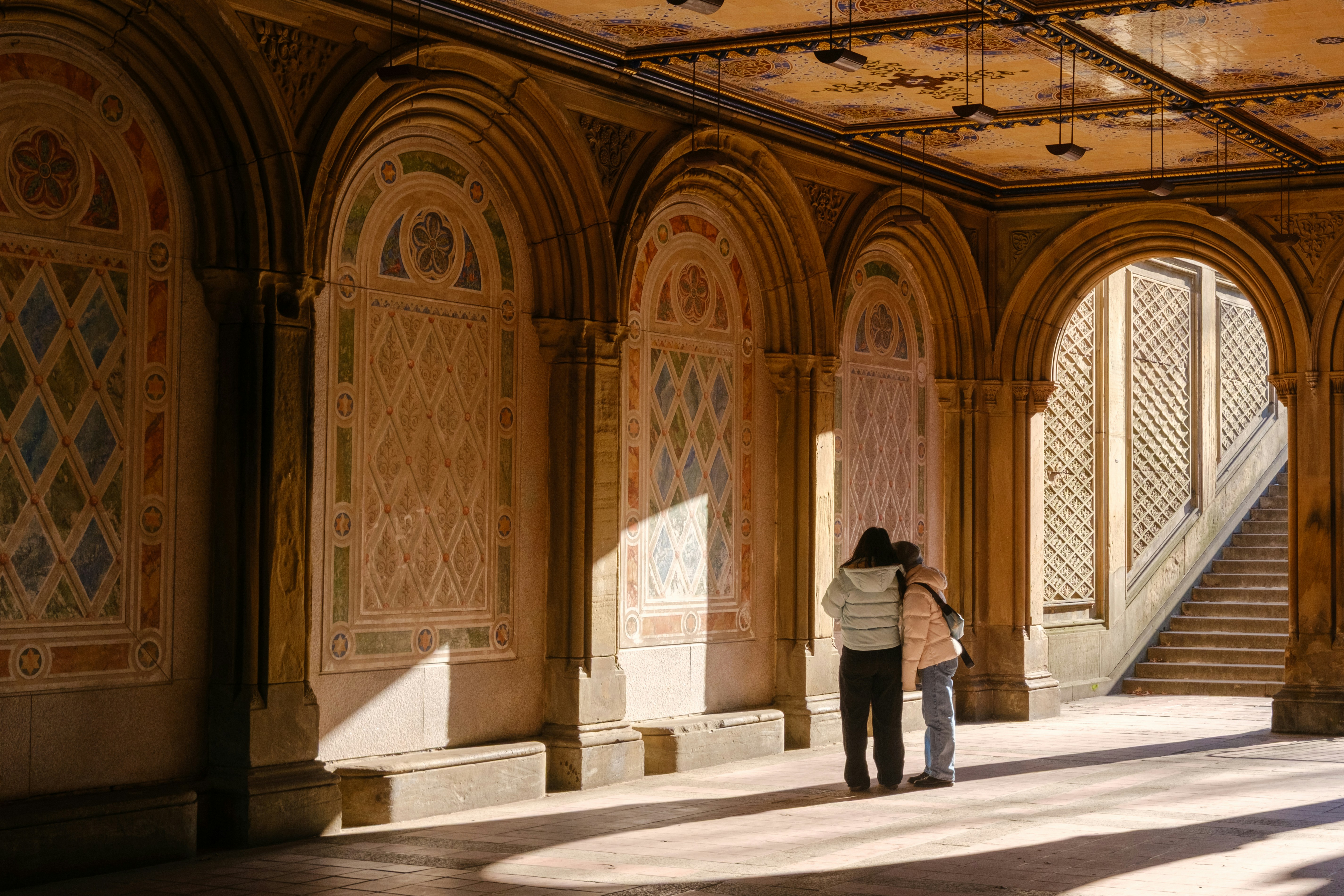 Two Figures in a Sunlit Arcade: Quiet Escape beneath Painted Arches