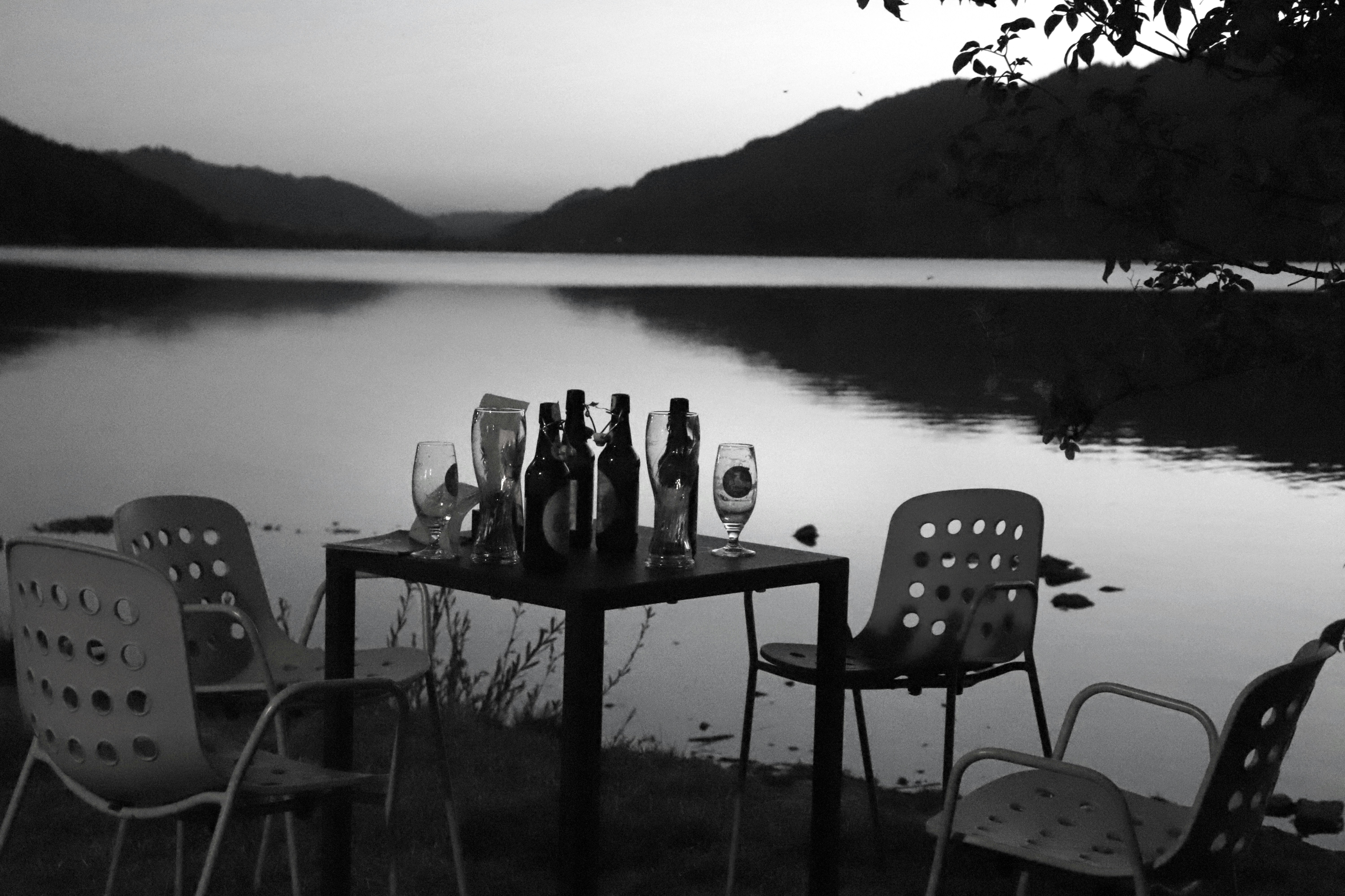 Evening at the Shore: Glasses and Bottle Silhouettes by the Lake