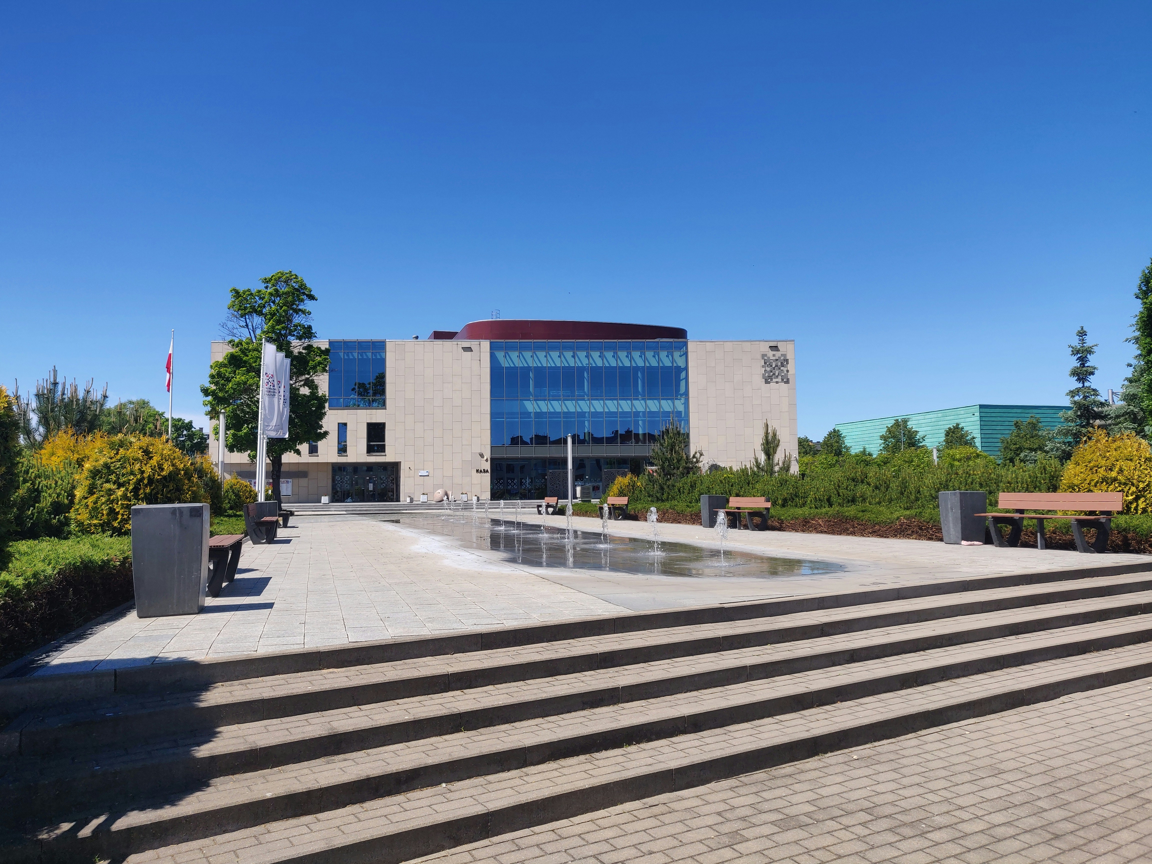 Modern campus plaza with a glass-fronted building and tiered steps