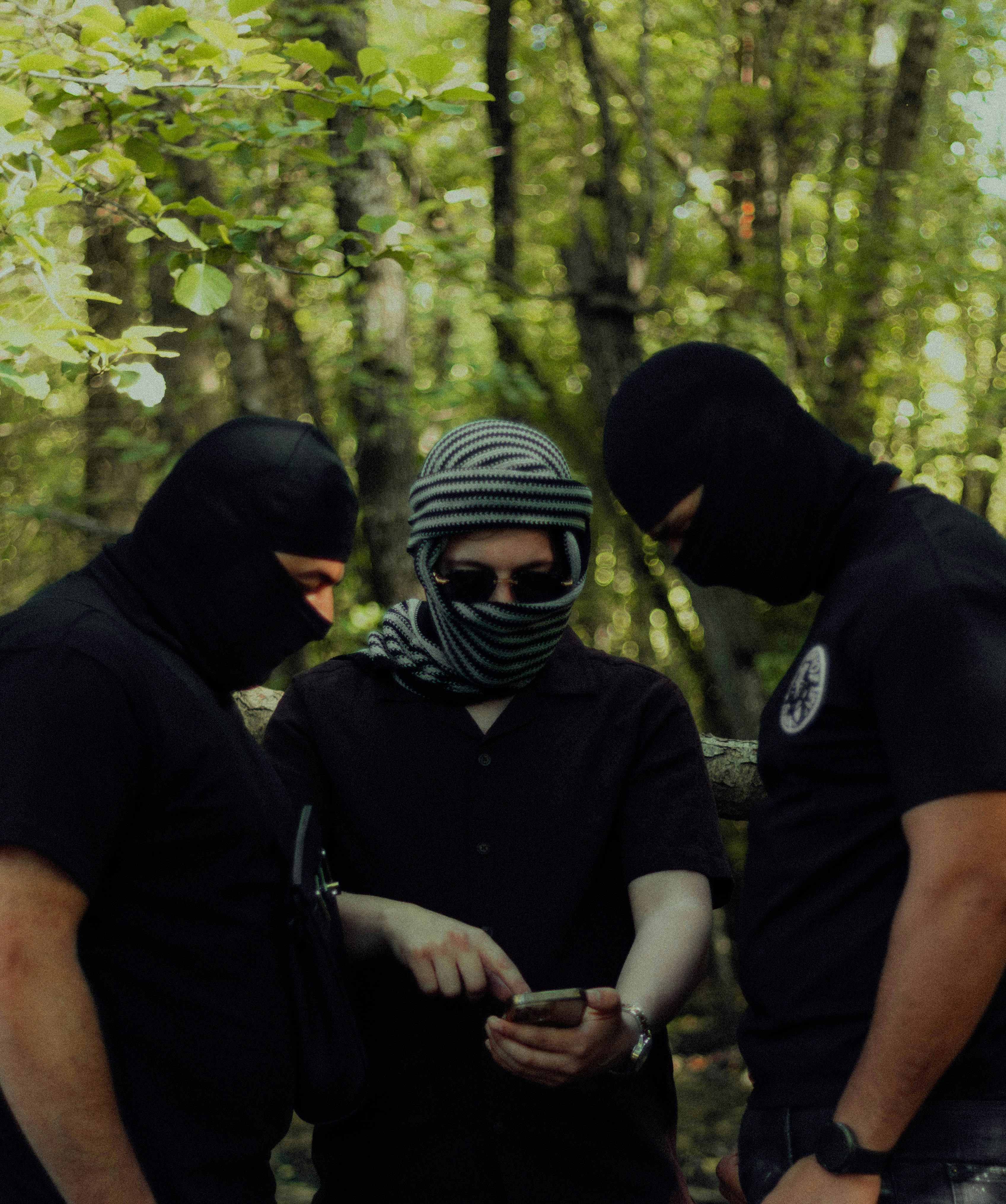 Masked Trio in the Forest: A Secretive Exchange Over a Smartphone