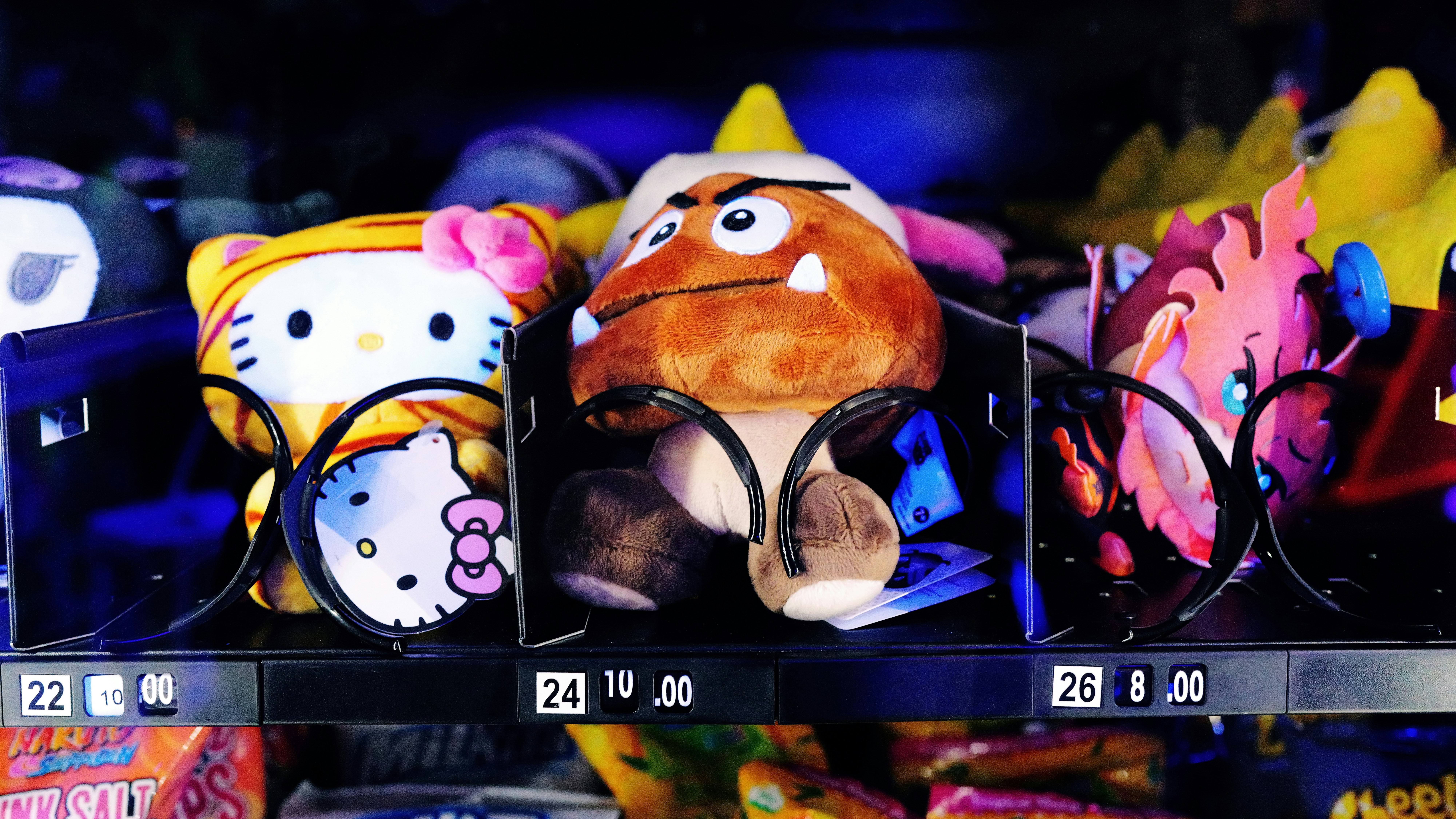 Hello kitty and goomba plushies in a vending machine.