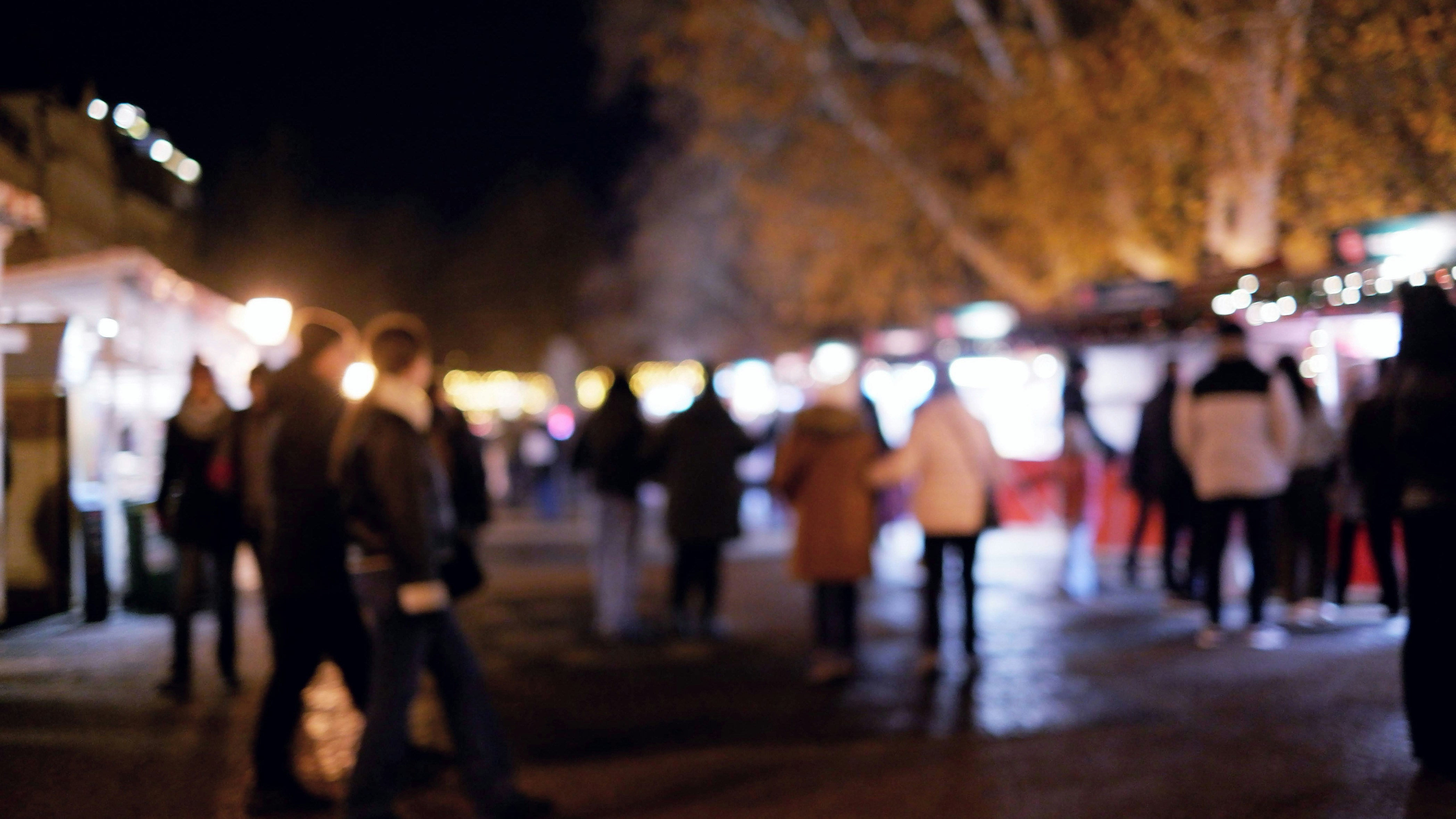 Blurred night scene with people walking at a festive market.