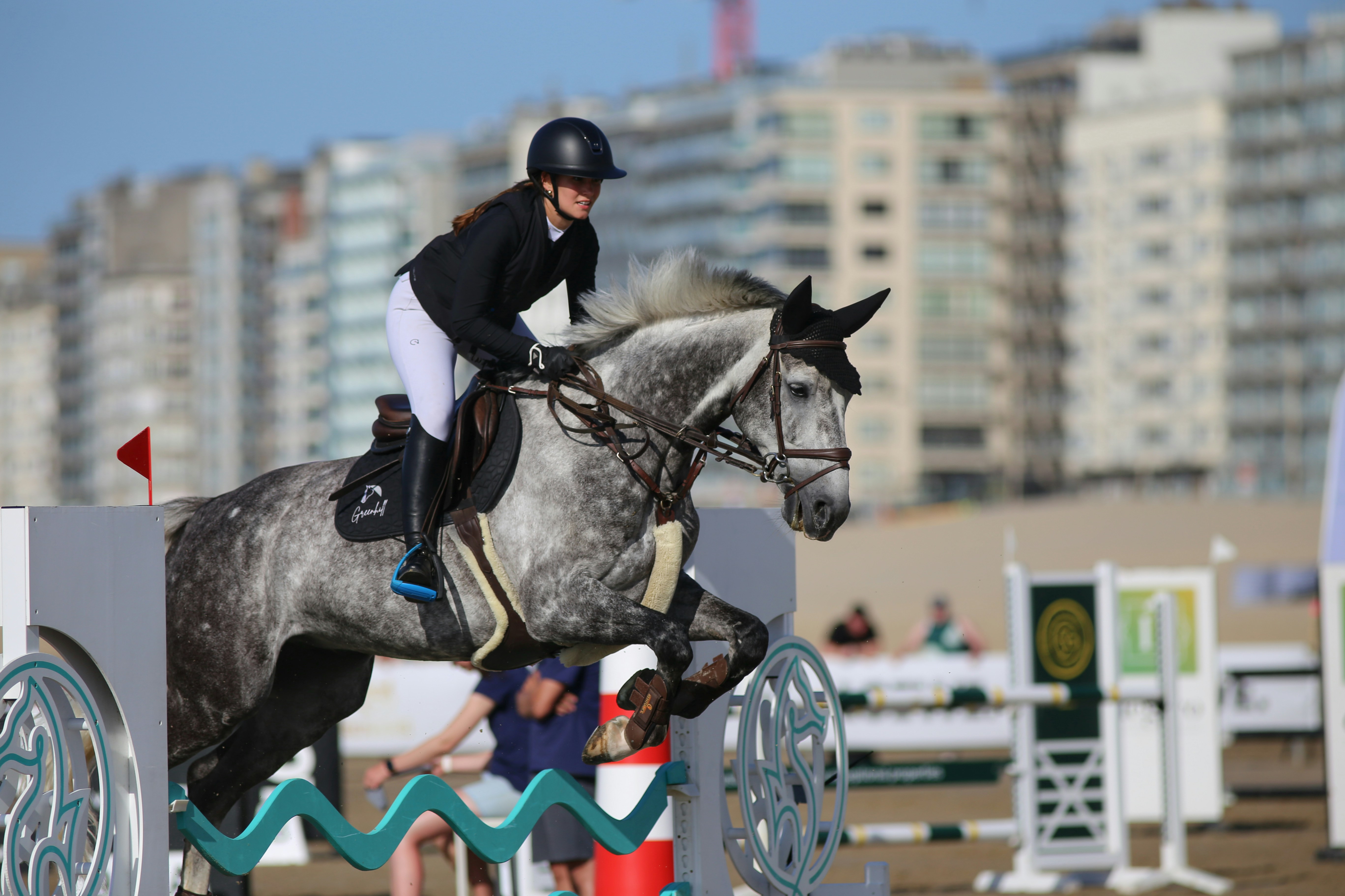 Leap of Focus: Youthful Rider Clears a Jump Against an Urban Backdrop