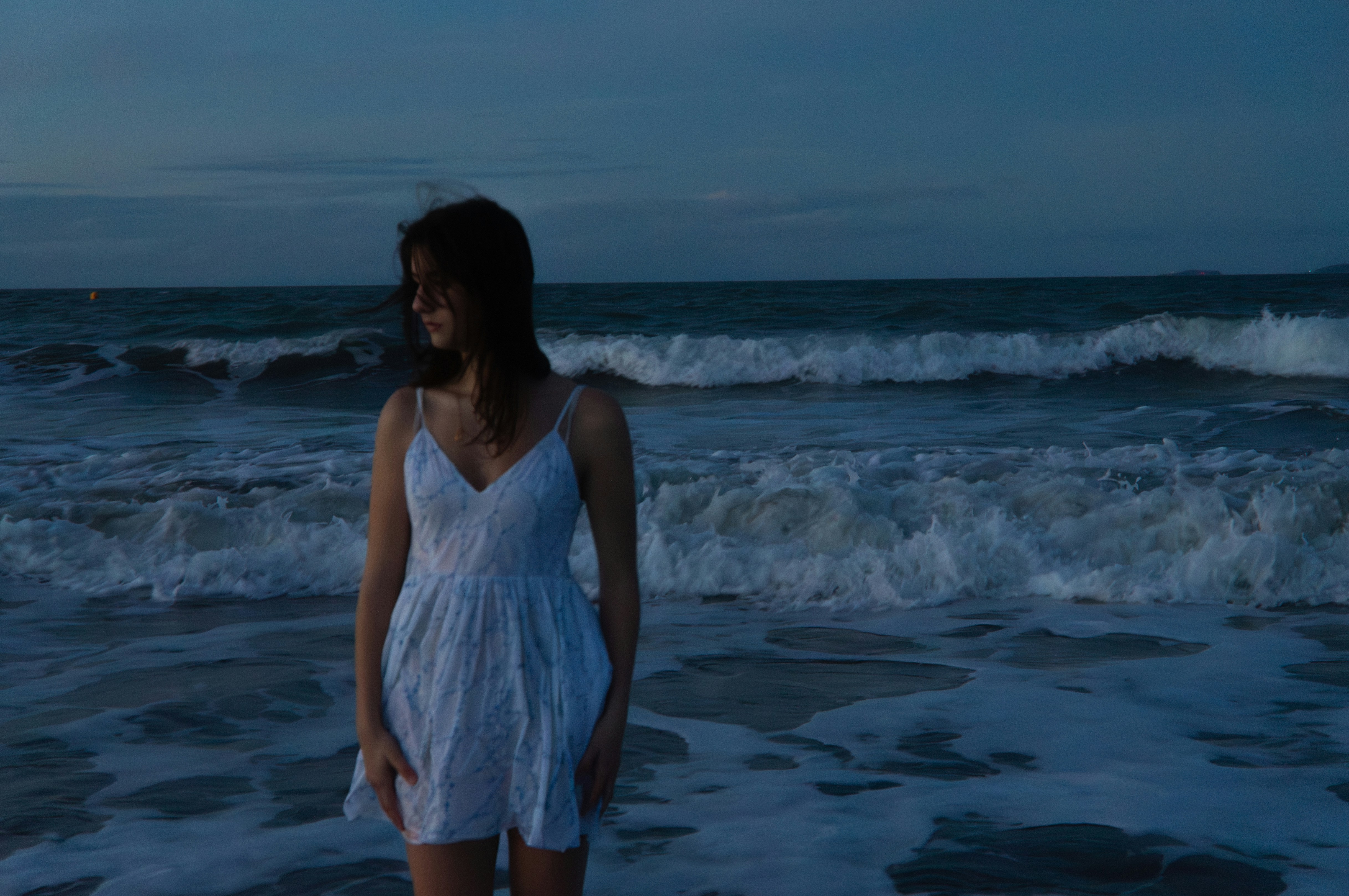 Coastal silhouette in twilight: a lone figure at the edge of surf