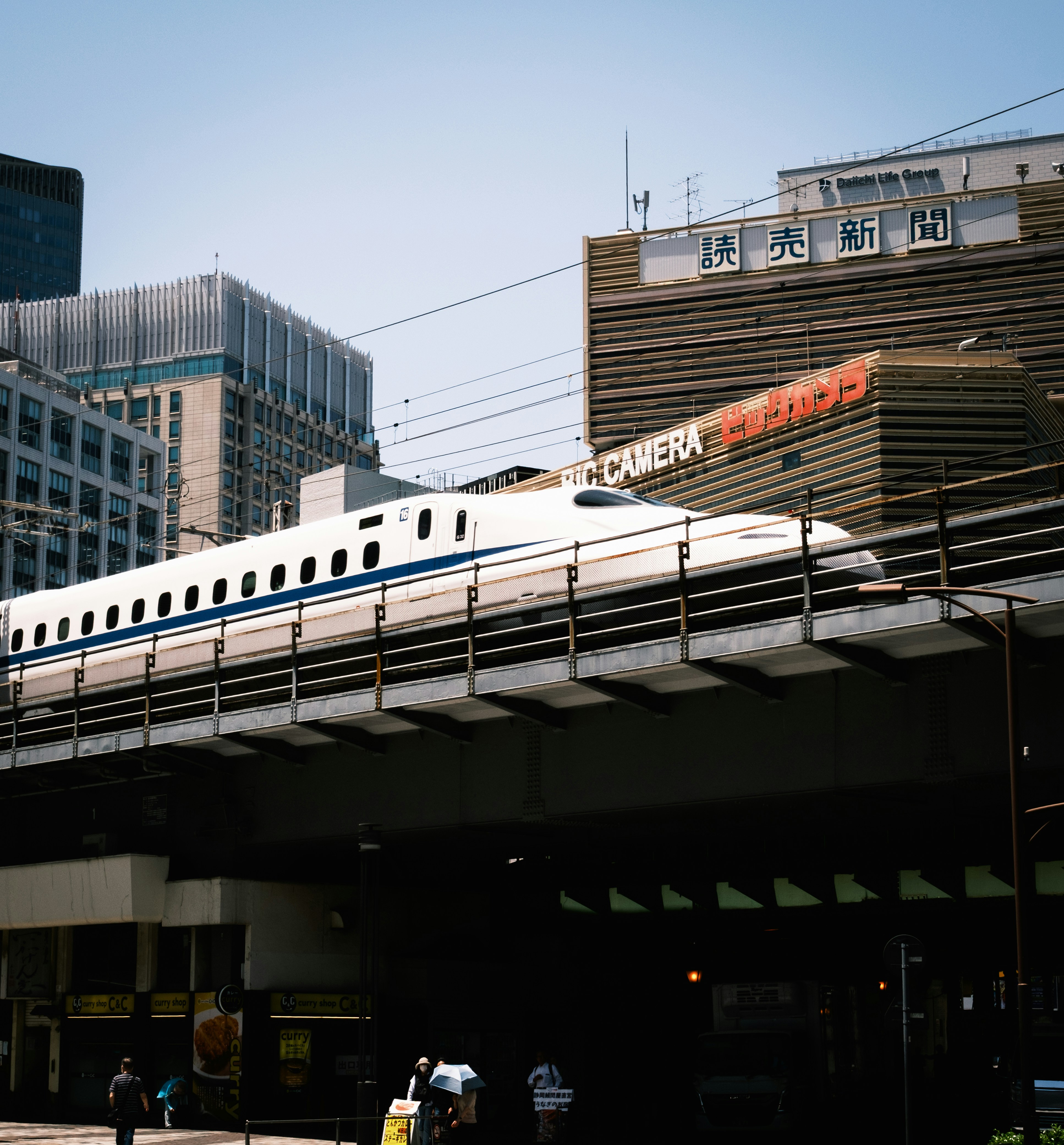 Tokyo Skyline Express: A Train Cleaving the City Above a Busy Pedestrian Crossing