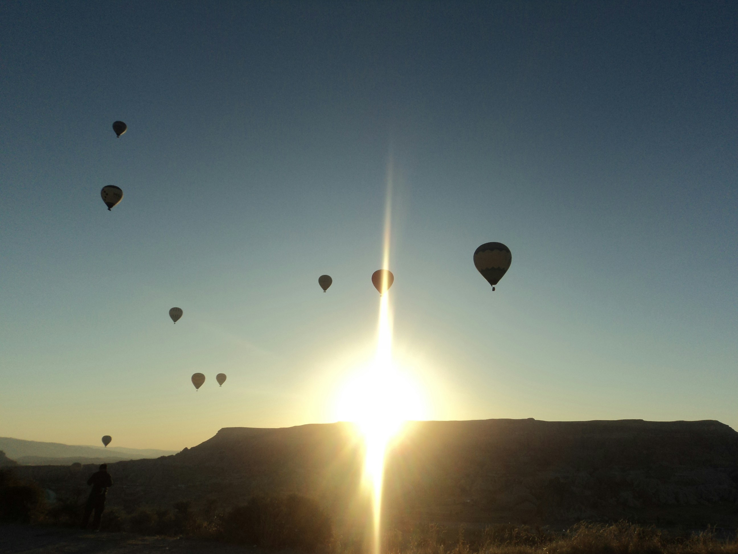 Ascending Dusk: Balloons Scatter Over a Desert Plateau