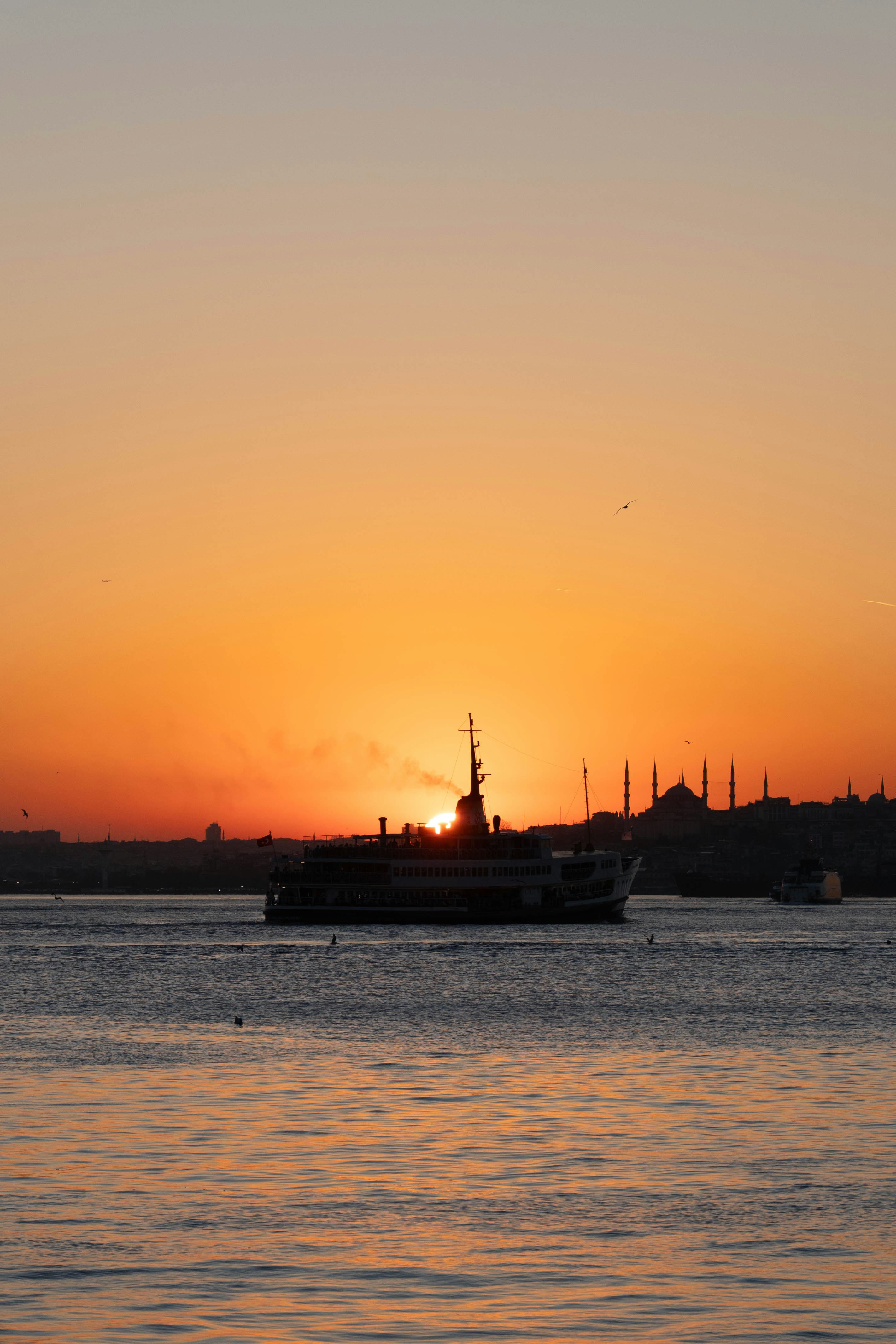 Sunset Over the Ferry: City Silhouette and Gentle Waves