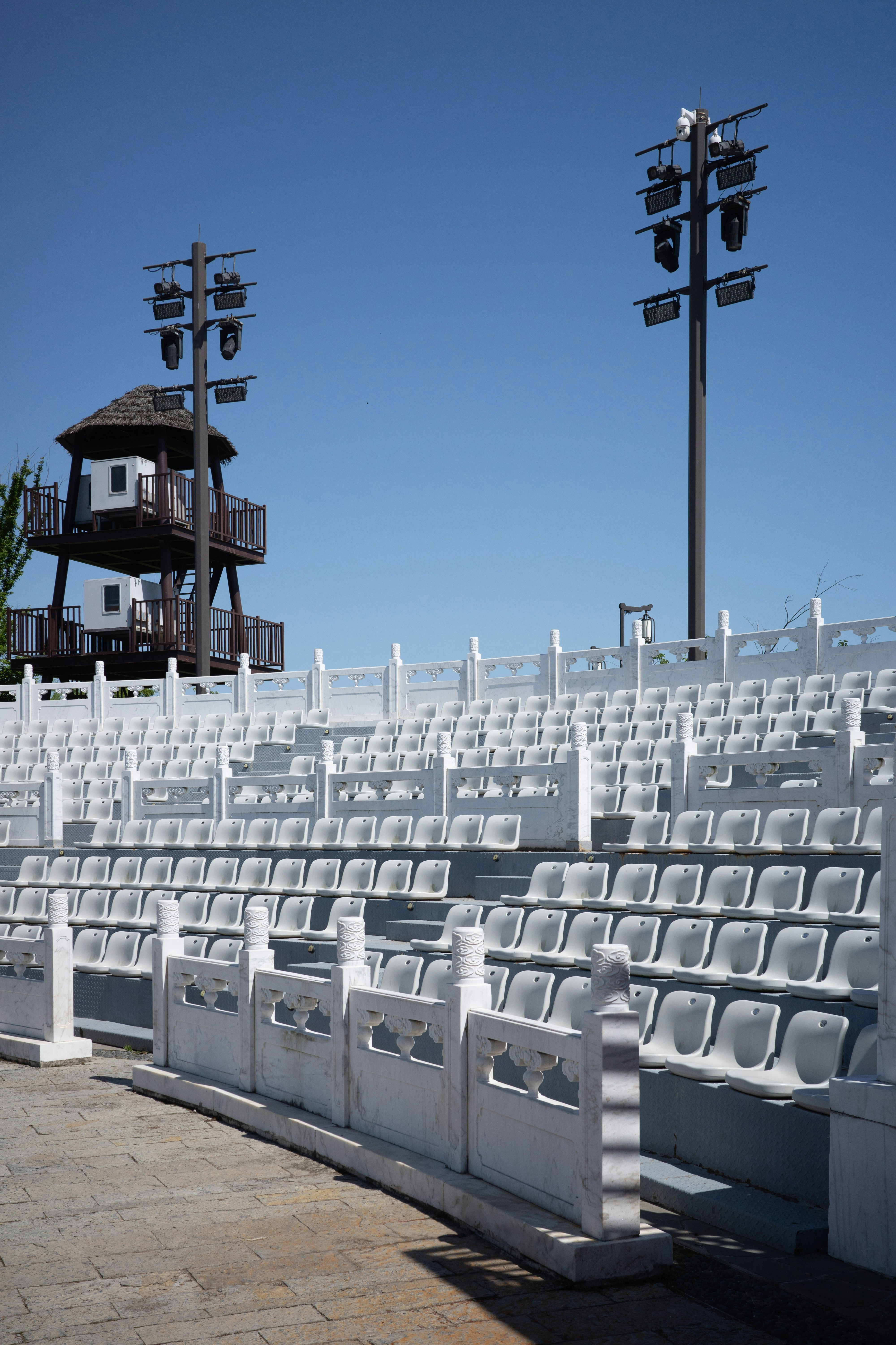 Empty stadium under a clear blue sky with a watchtower and floodlights