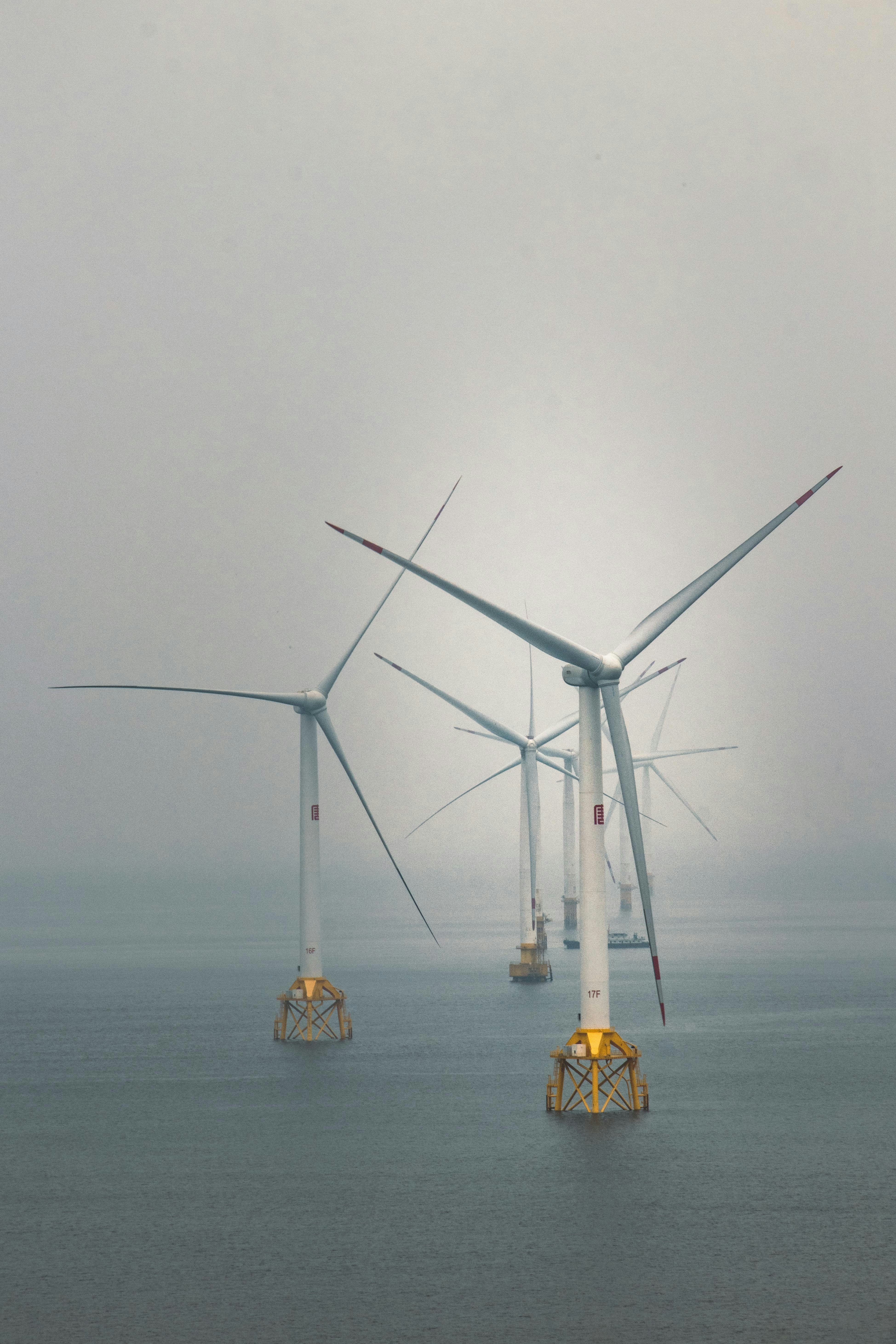 Offshore Giants: A Row of Wind Turbines Standing Against Misty Seas
