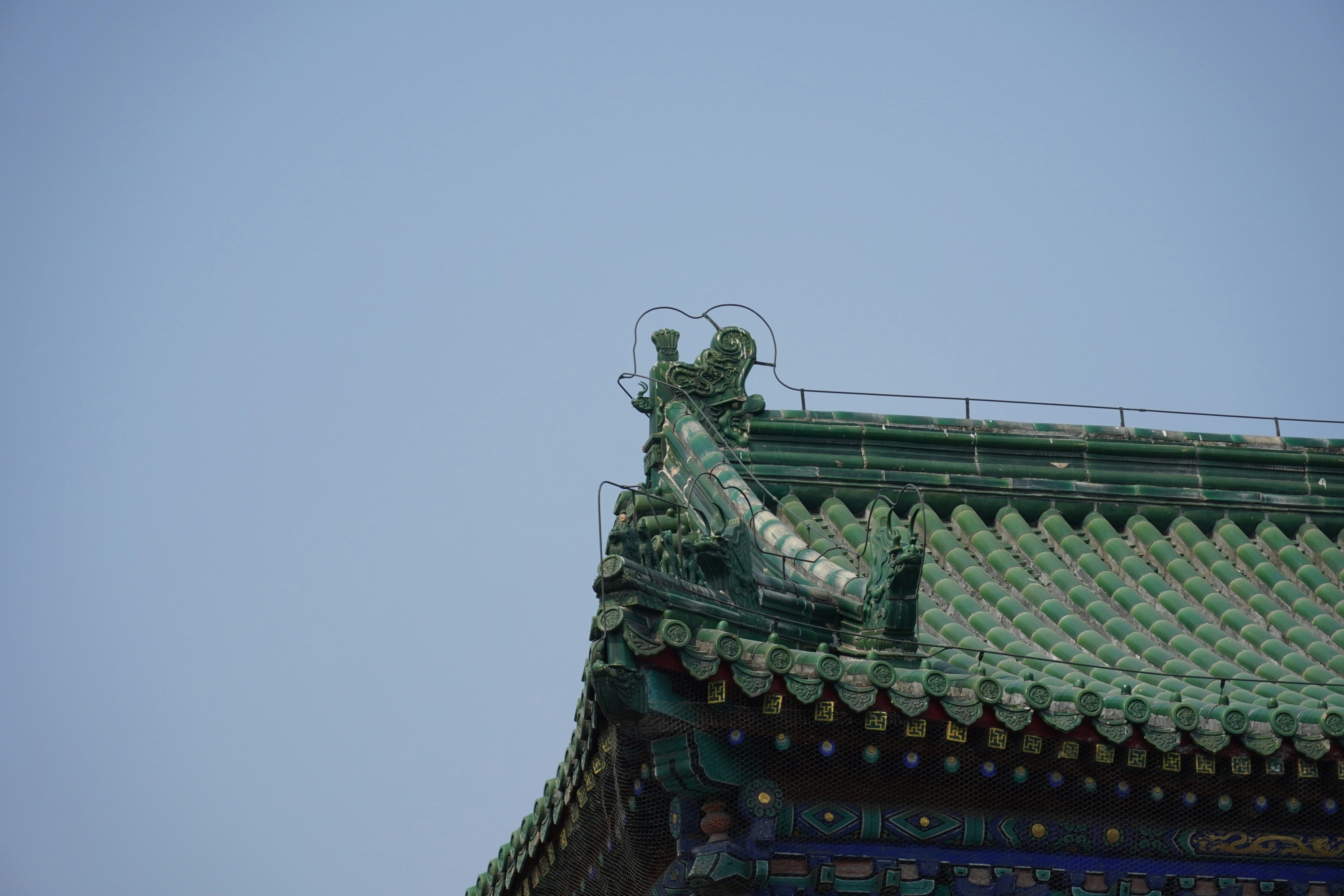 Green Roofline Edge: A Corner of Heritage Against a Clear Sky