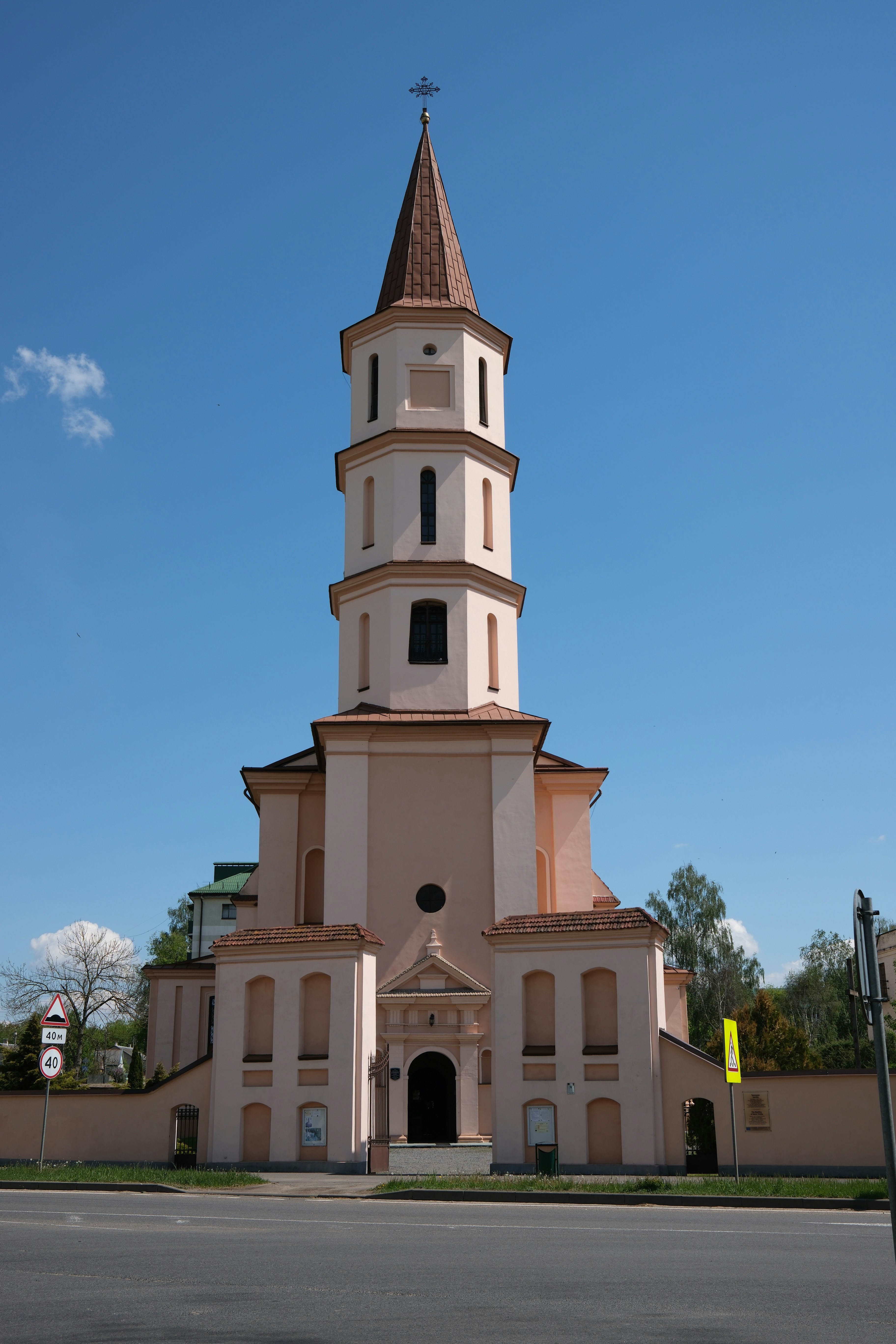 Towering Uhrturm: A peach-hued church spire under a clear blue sky