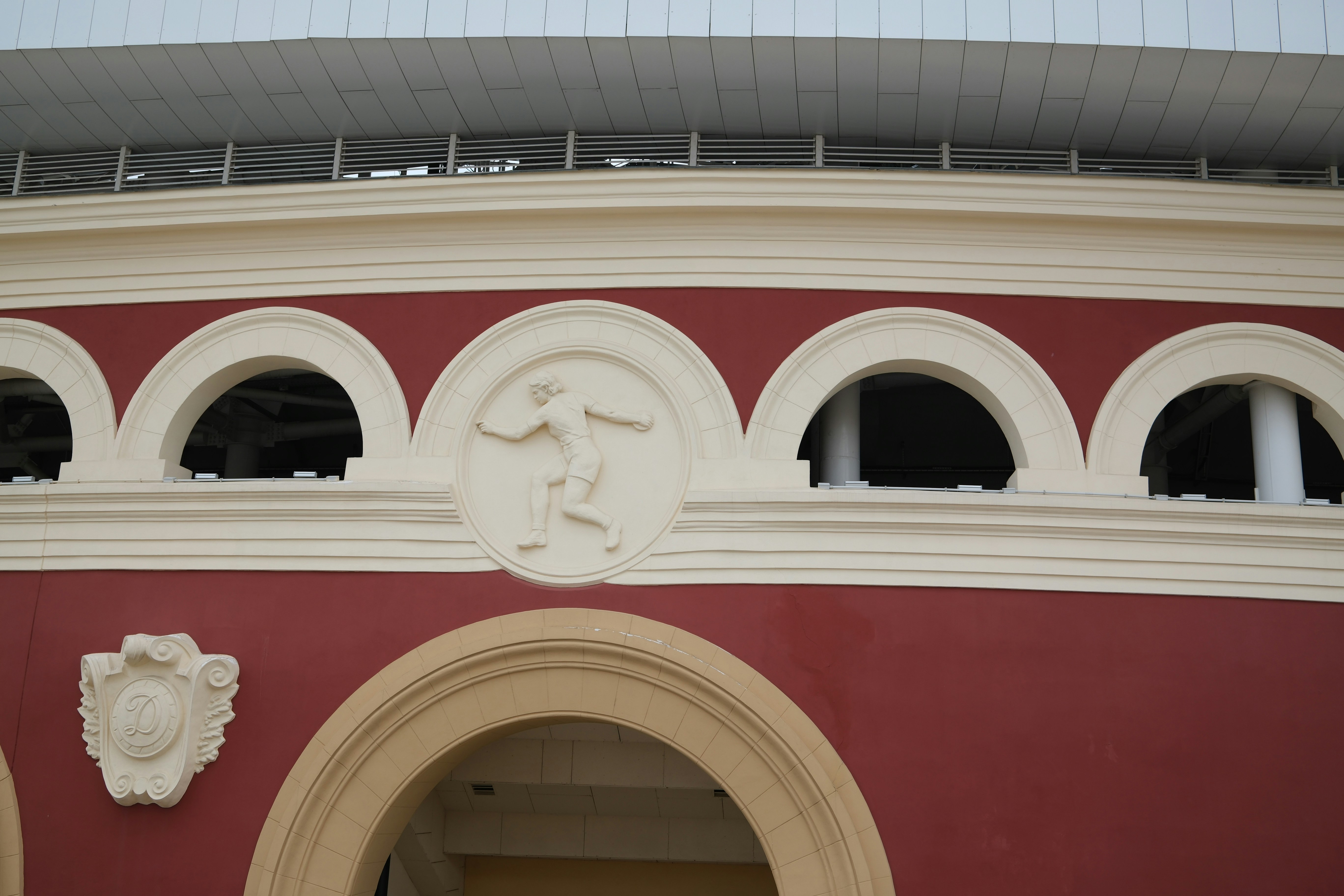 Archway Crest: Classical Reliefs Above a Red Facade