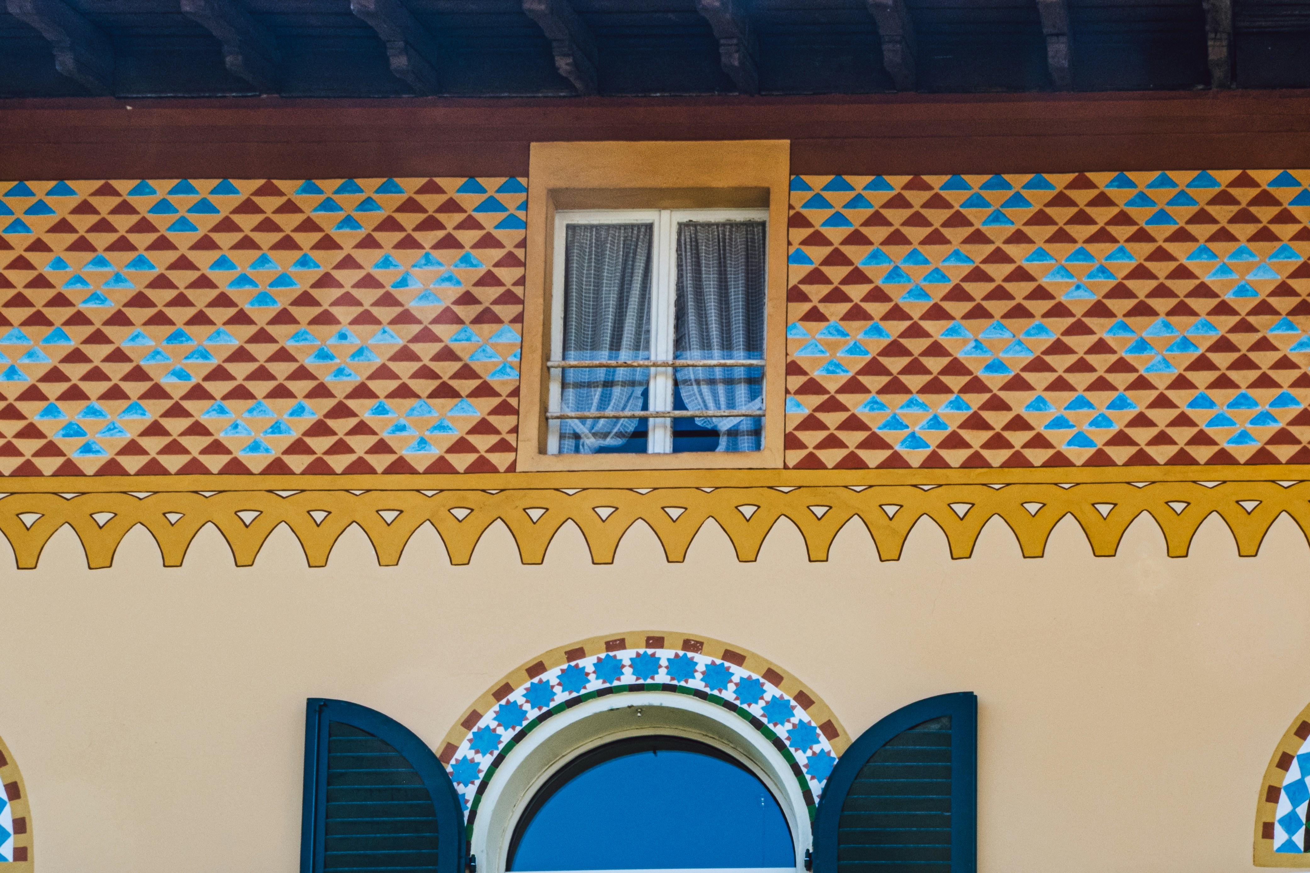 A colourful and dramatic example of soffit painting, in a brown and blue palette, which extends to the arches above the upper level windows.