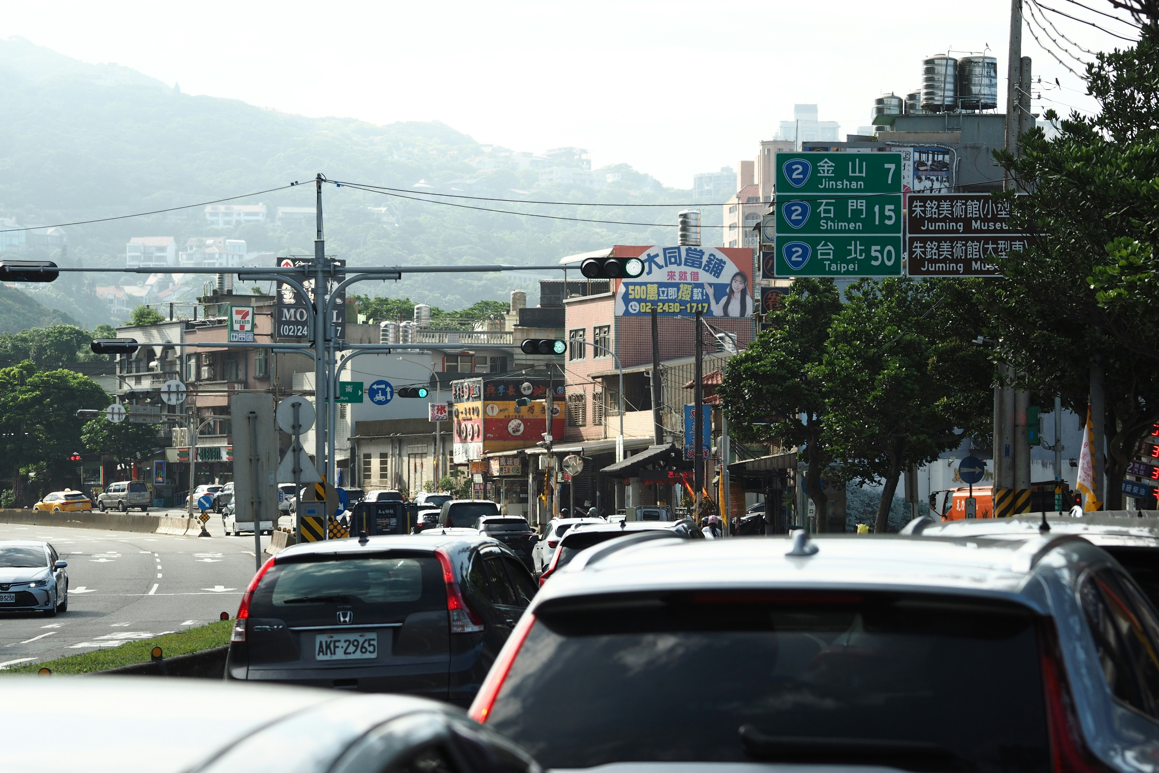 Cars in traffic on a city street with mountains.