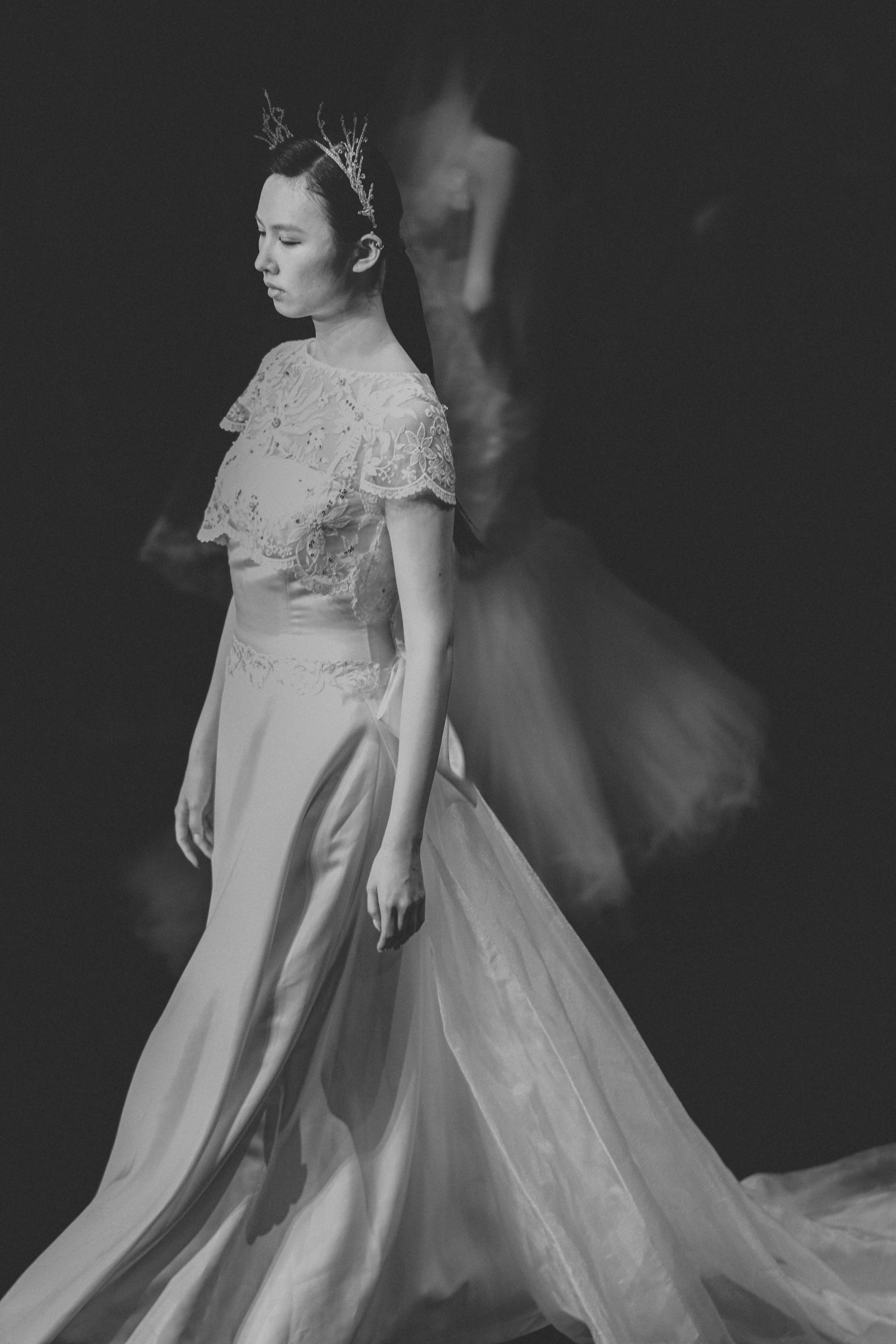 Woman in elegant dress and crown with ghostly figure.