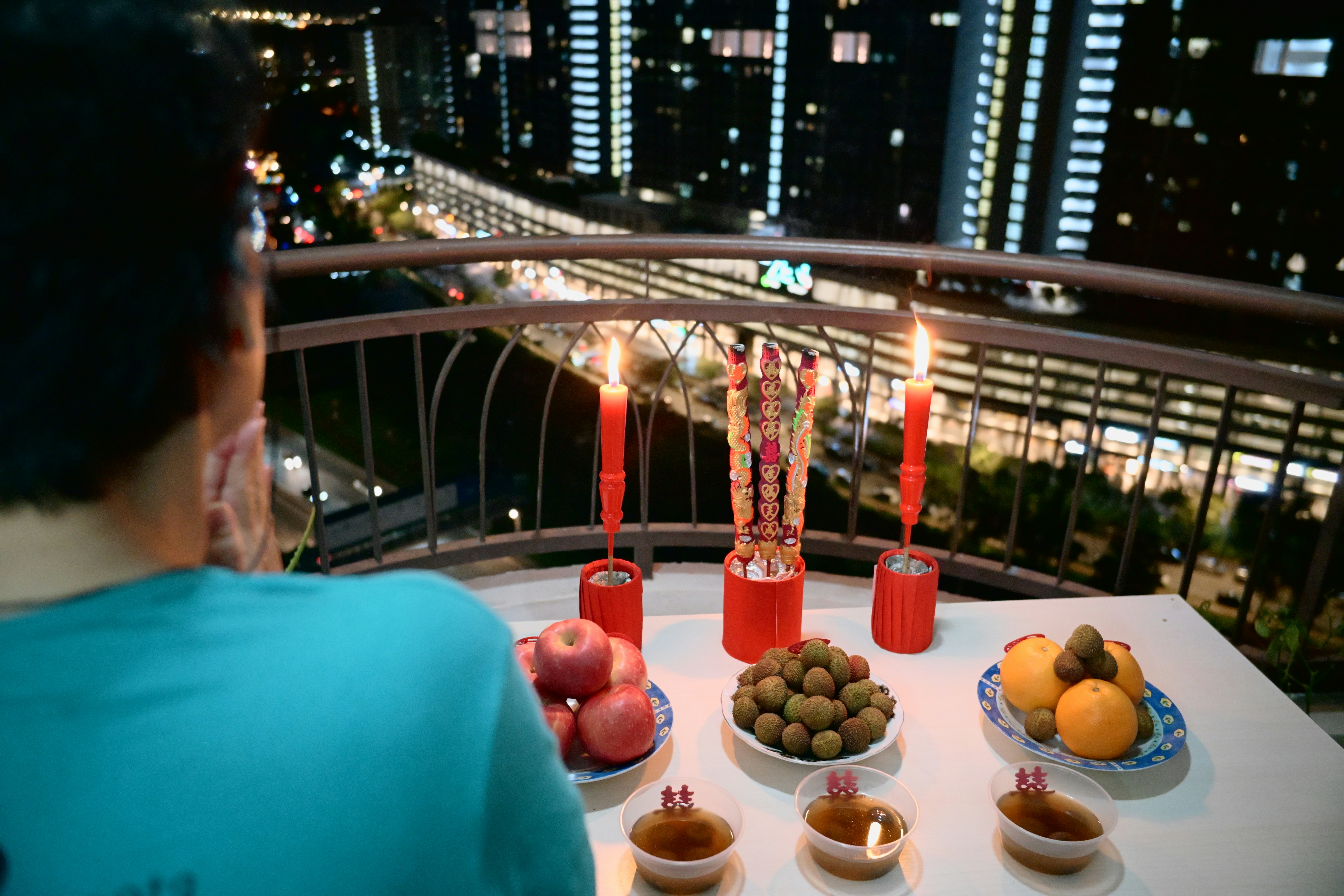 Balcony offerings with lit candles and city night view.