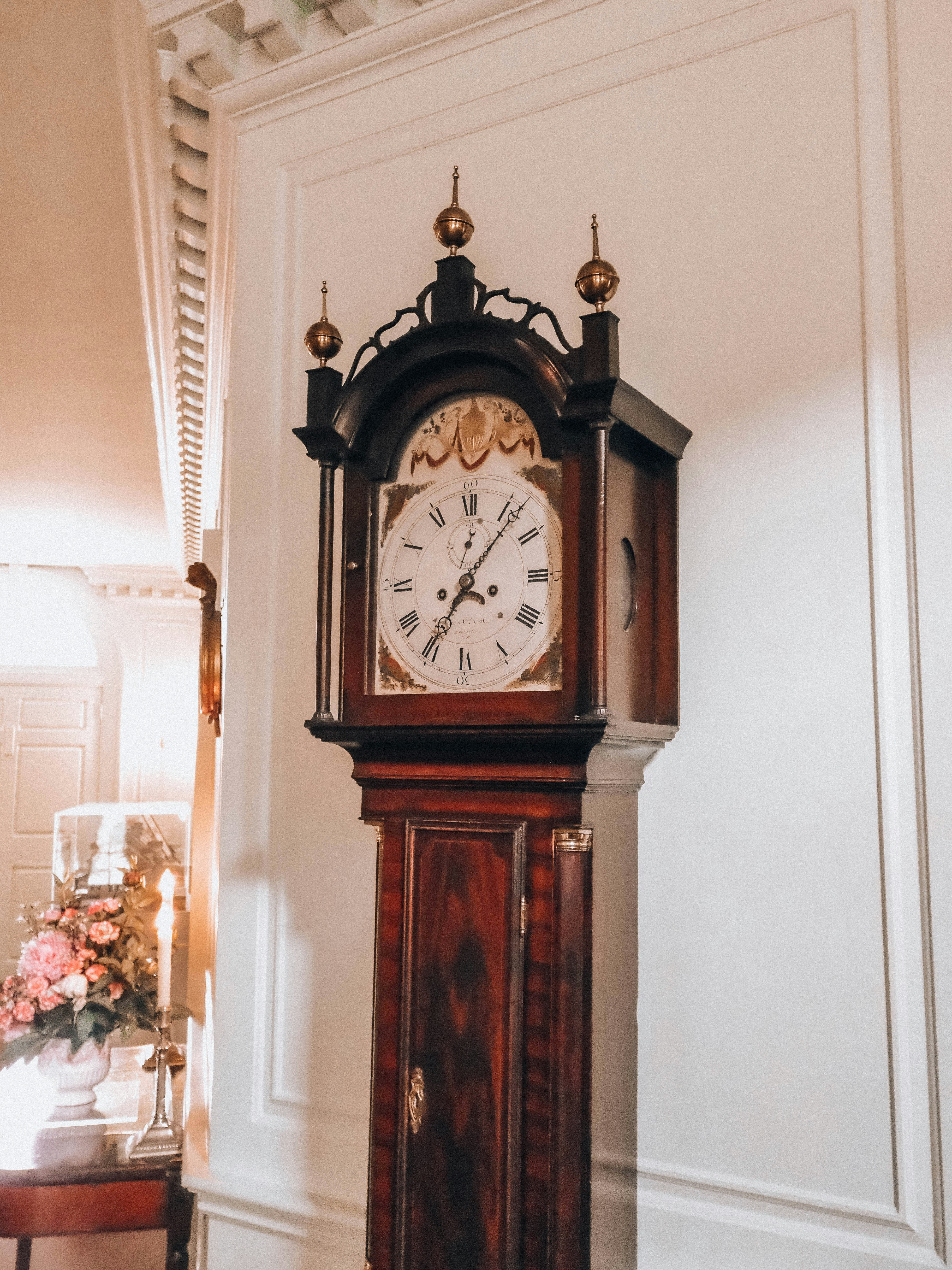 An antique wooden grandfather clock stands in a well-decorated room.