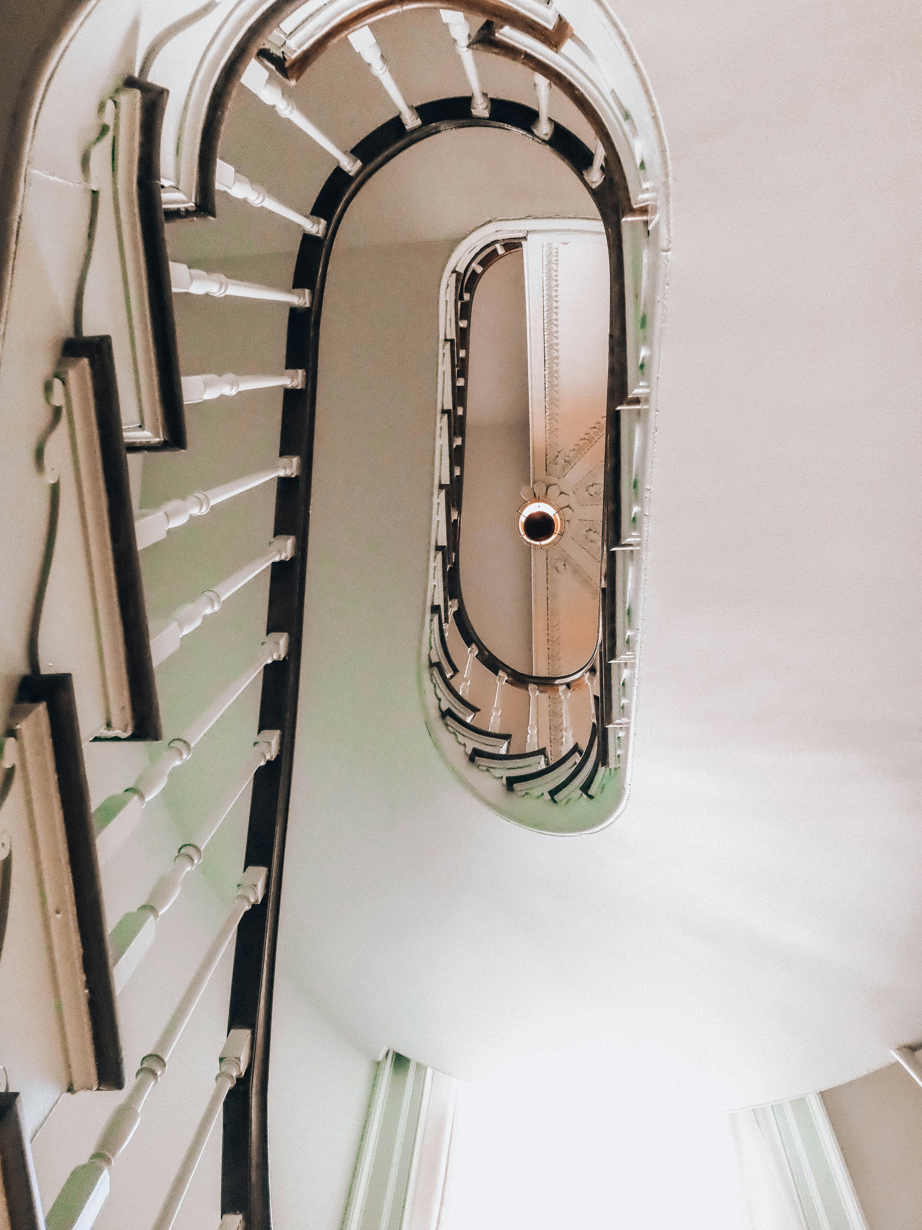 Elegant white spiral staircase with dark wood accents.