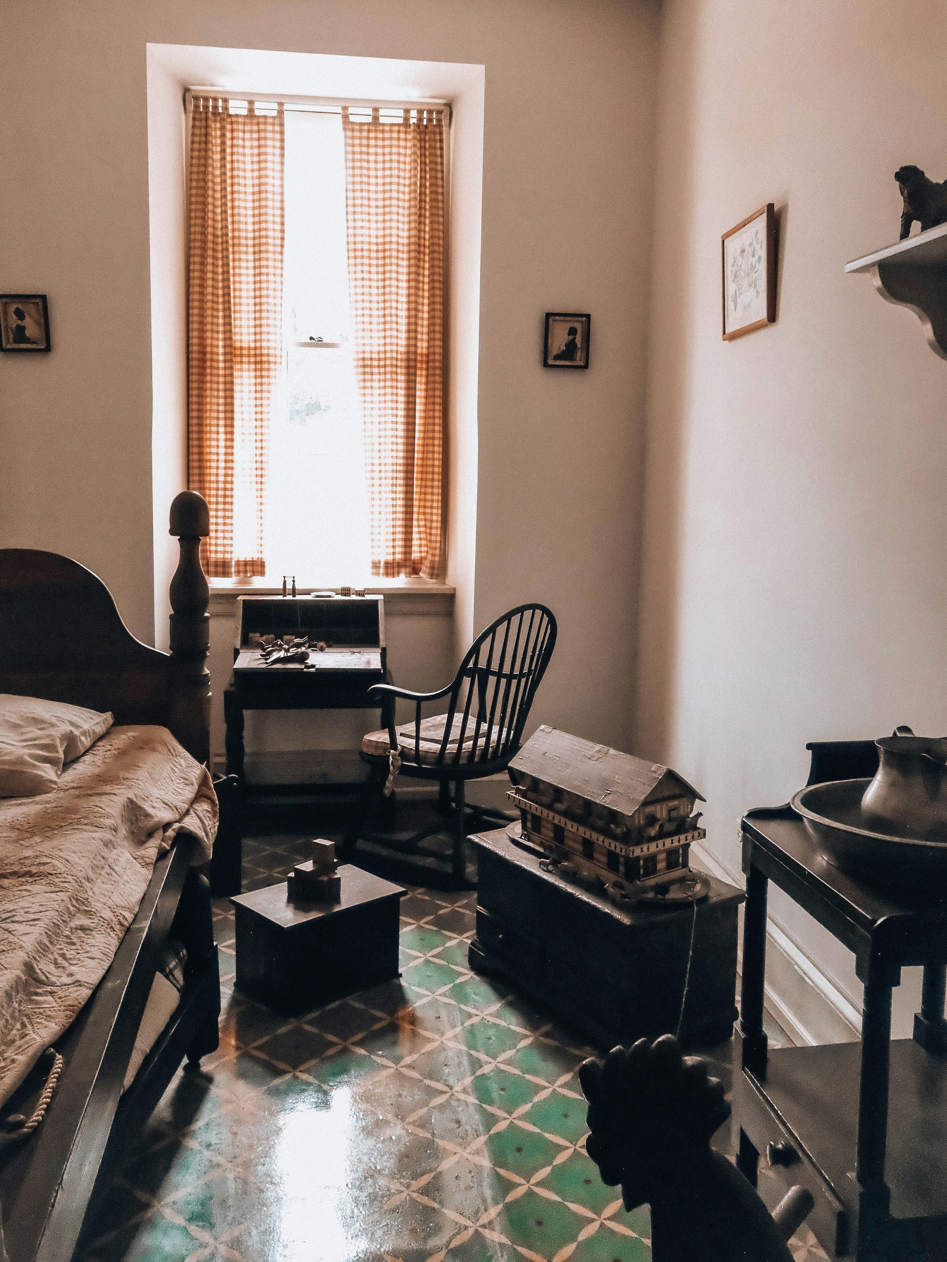 An old-fashioned room with a bed, desk, and patterned floor.