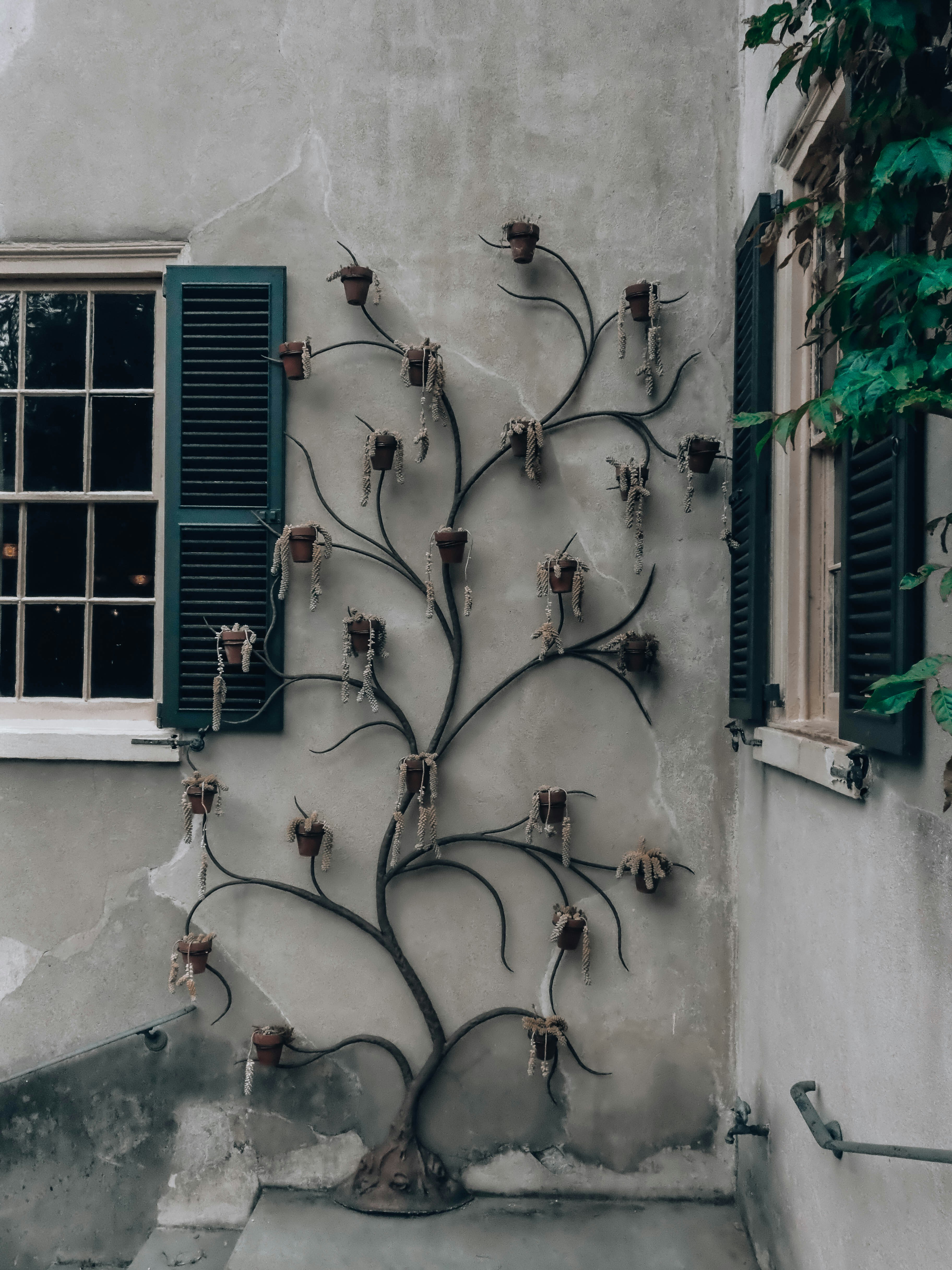 Decorative metal tree sculpture on a weathered stucco wall.