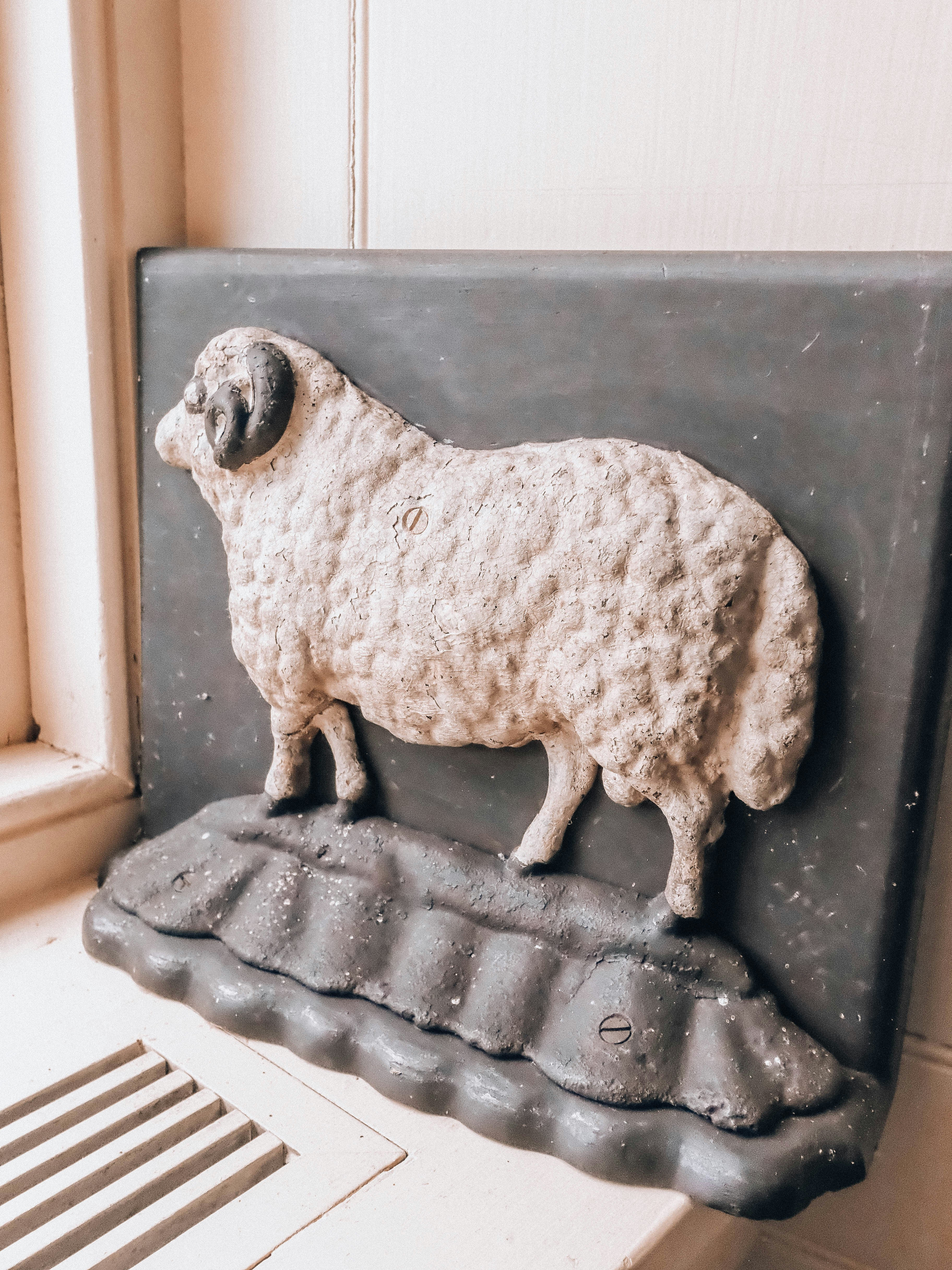 An old white cast-iron sheep doorstop on a windowsill.