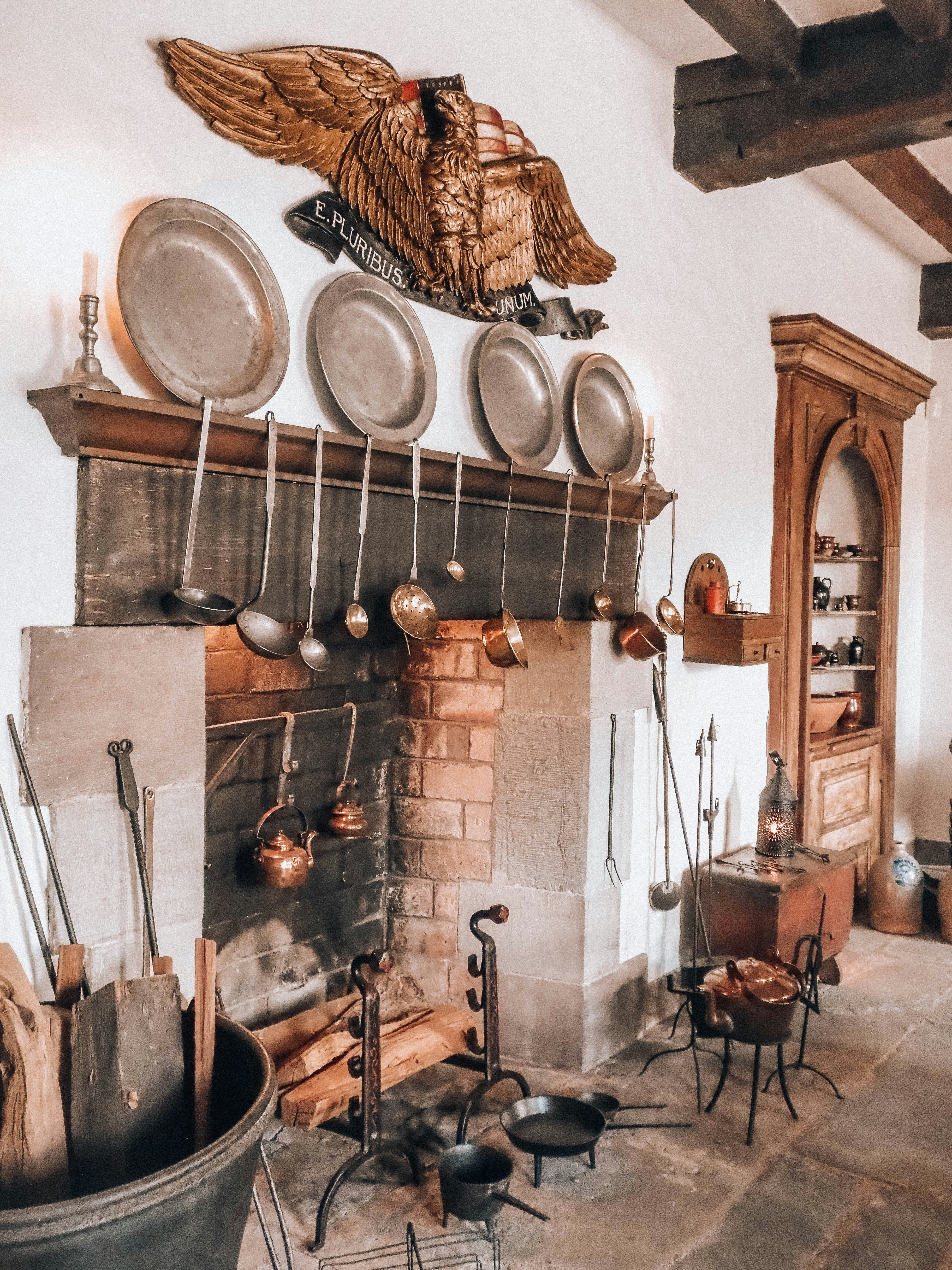 Vintage kitchen fireplace with cooking utensils and a decorative eagle.