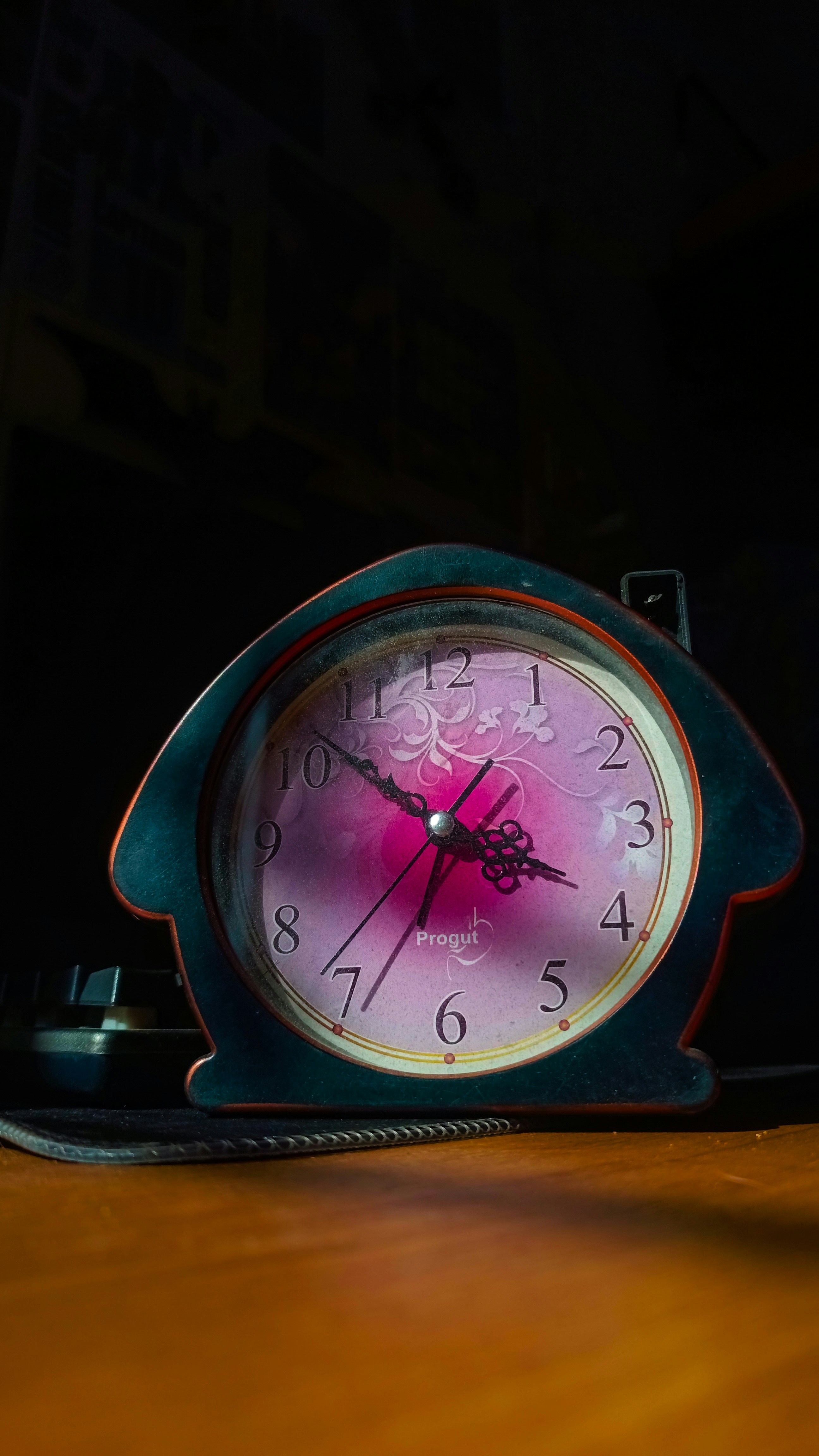 Sunlight illuminates a house-shaped alarm clock with a pink face.