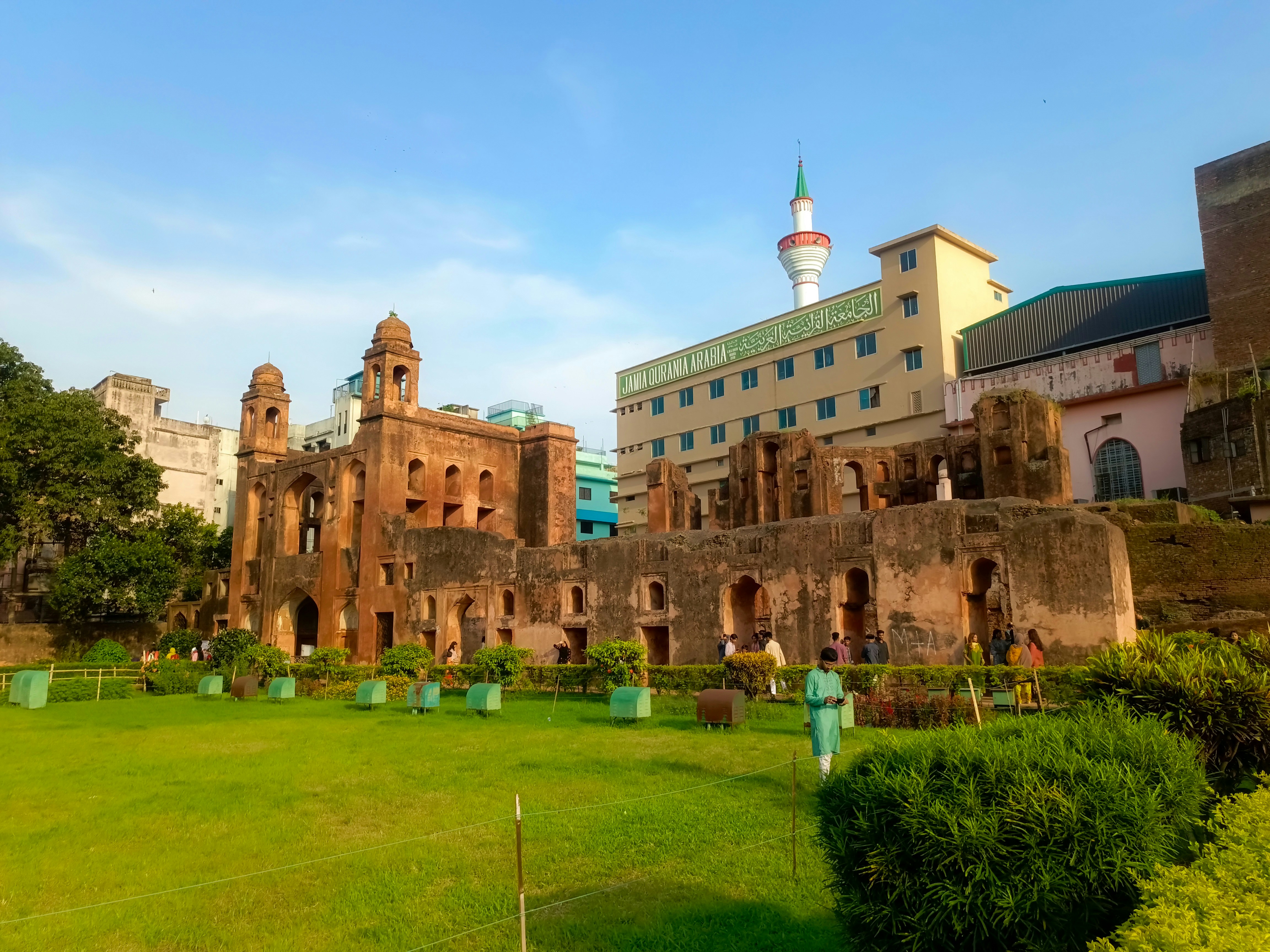 Ancient brick ruins and a green lawn under blue sky.