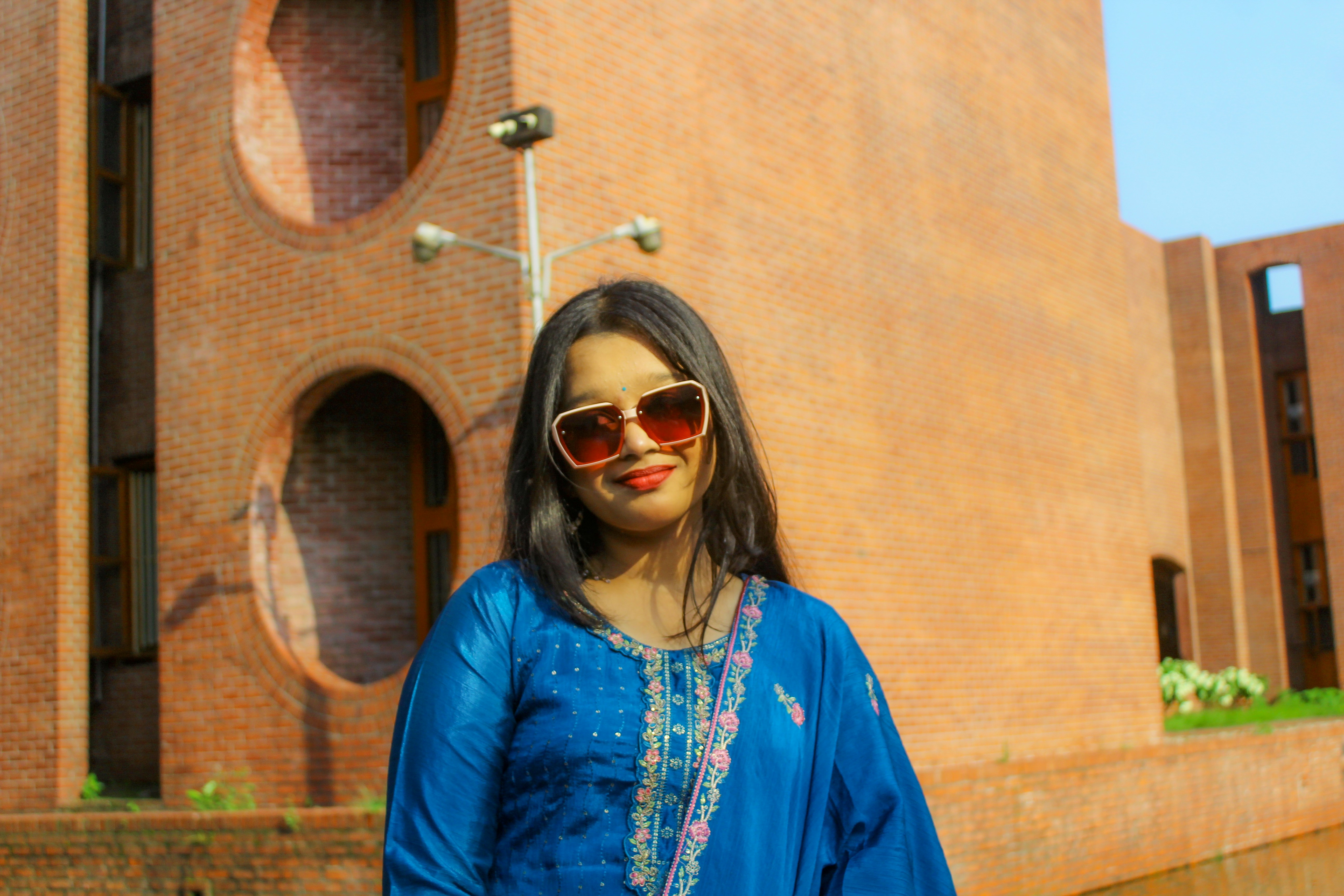 Blue Attire, Brick Backdrop: A Portrait in Soft Focus and Warm Light
