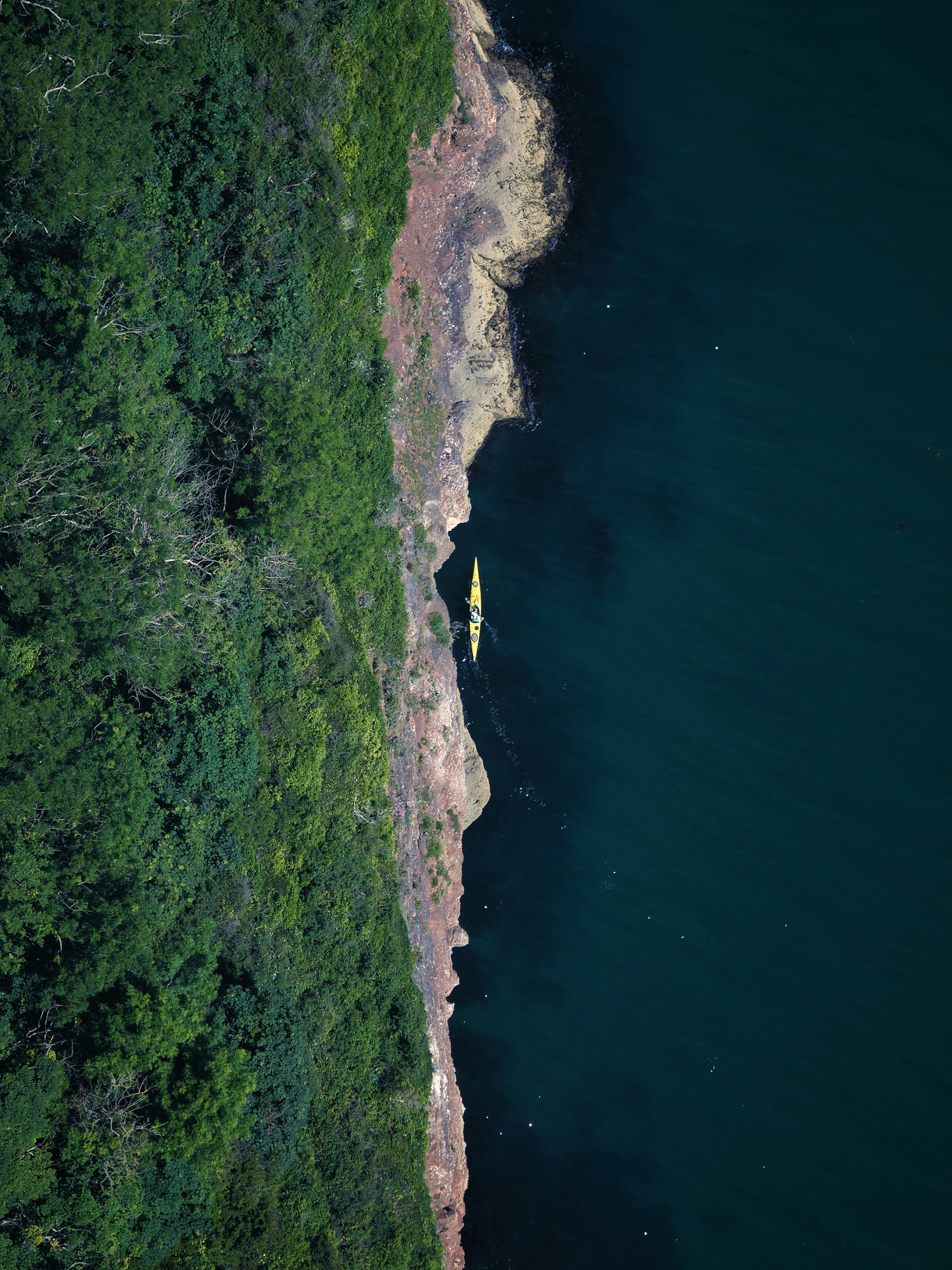 Close To The Edge. Lone kayaker tracing the cliffs along the coast of Babbacombe, Devon, UK