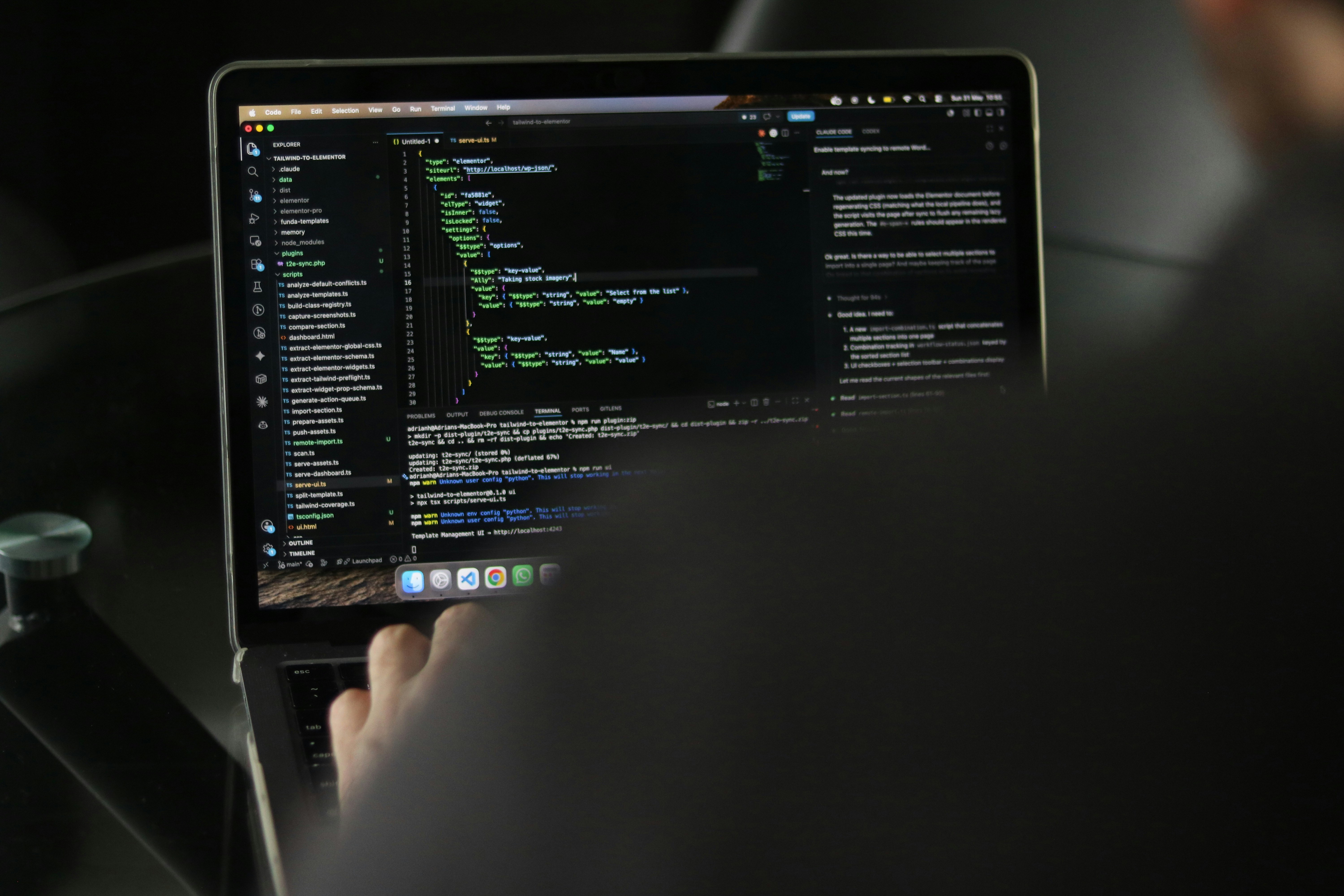Close-up of a laptop screen displaying code, with a blurred foreground suggesting a person working intently. A tech workstation scene highlighting programming activity.