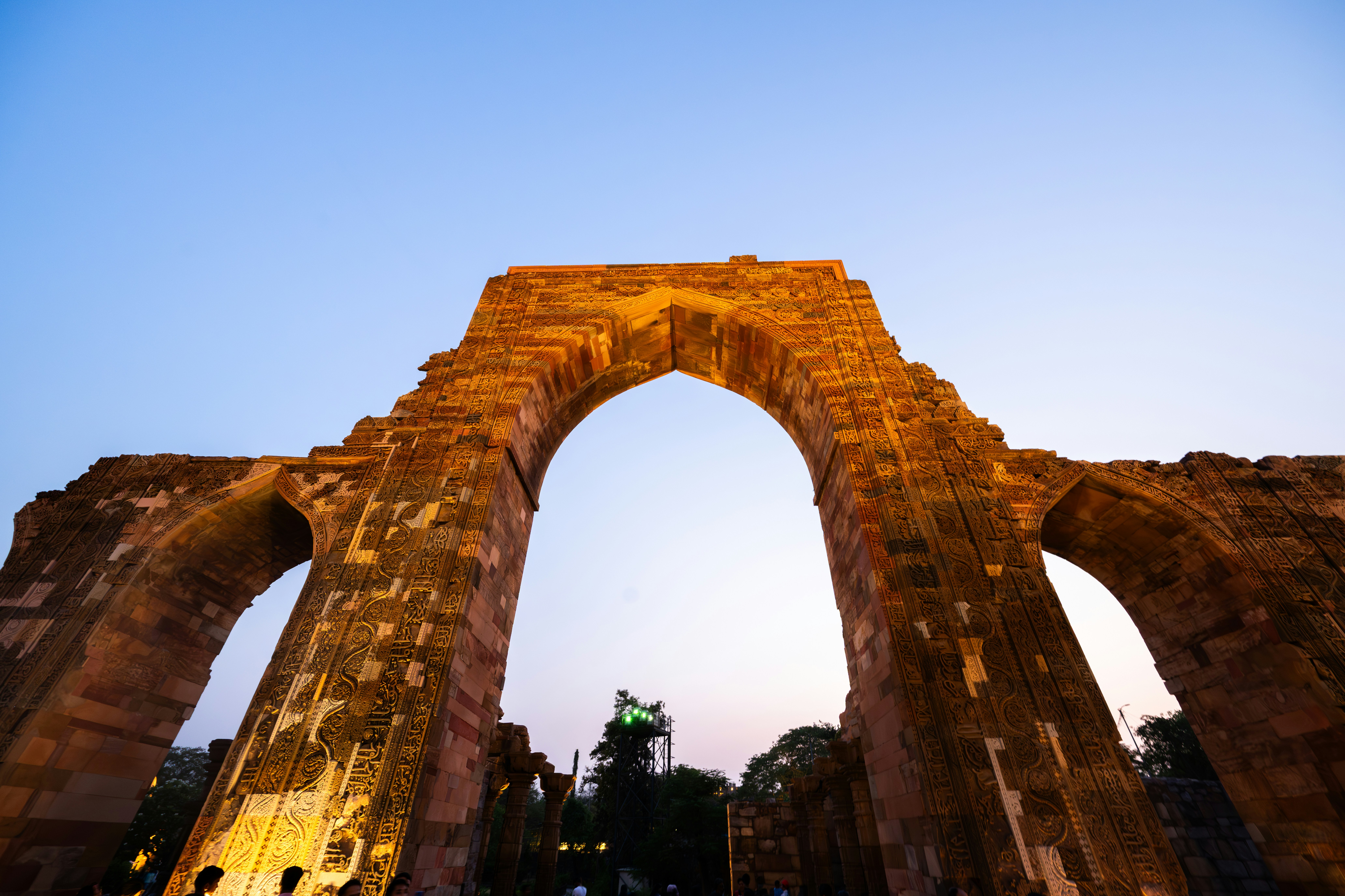 Ancient stone archway illuminated at dusk against a clear sky.