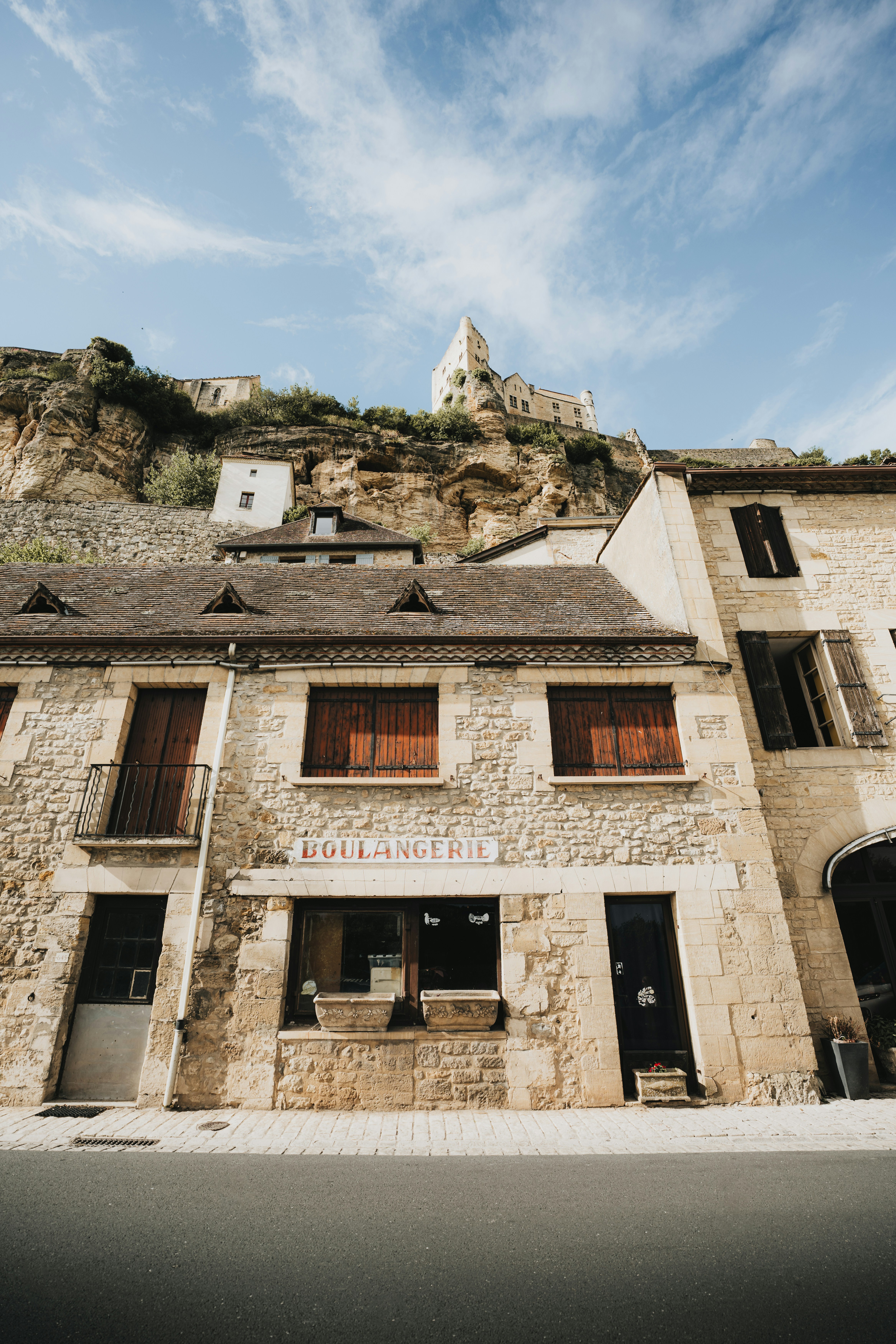 Stone bakery beneath a hilltop fortress in a sunlit village