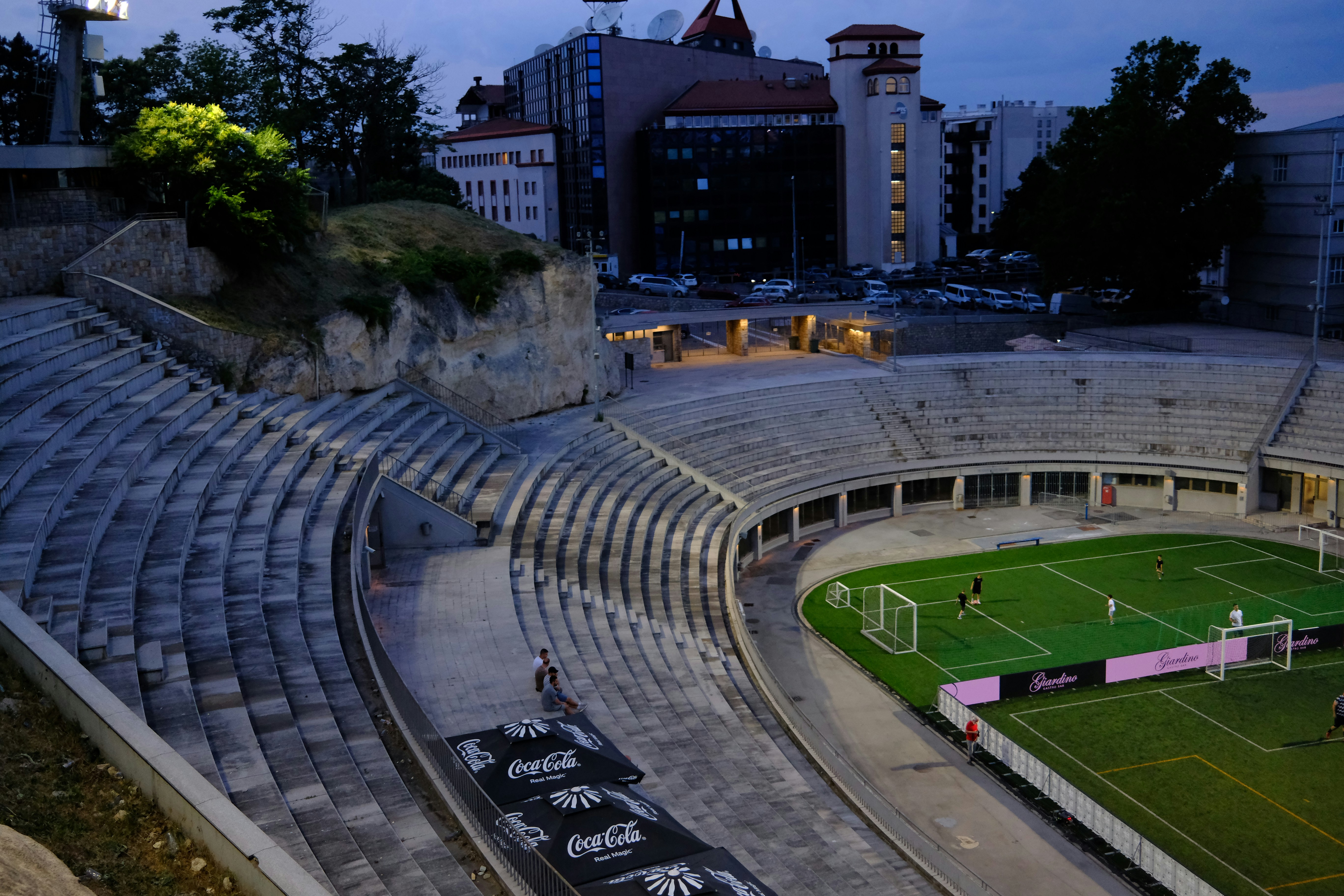 Football stadium with tiered seating and city buildings at dusk.
