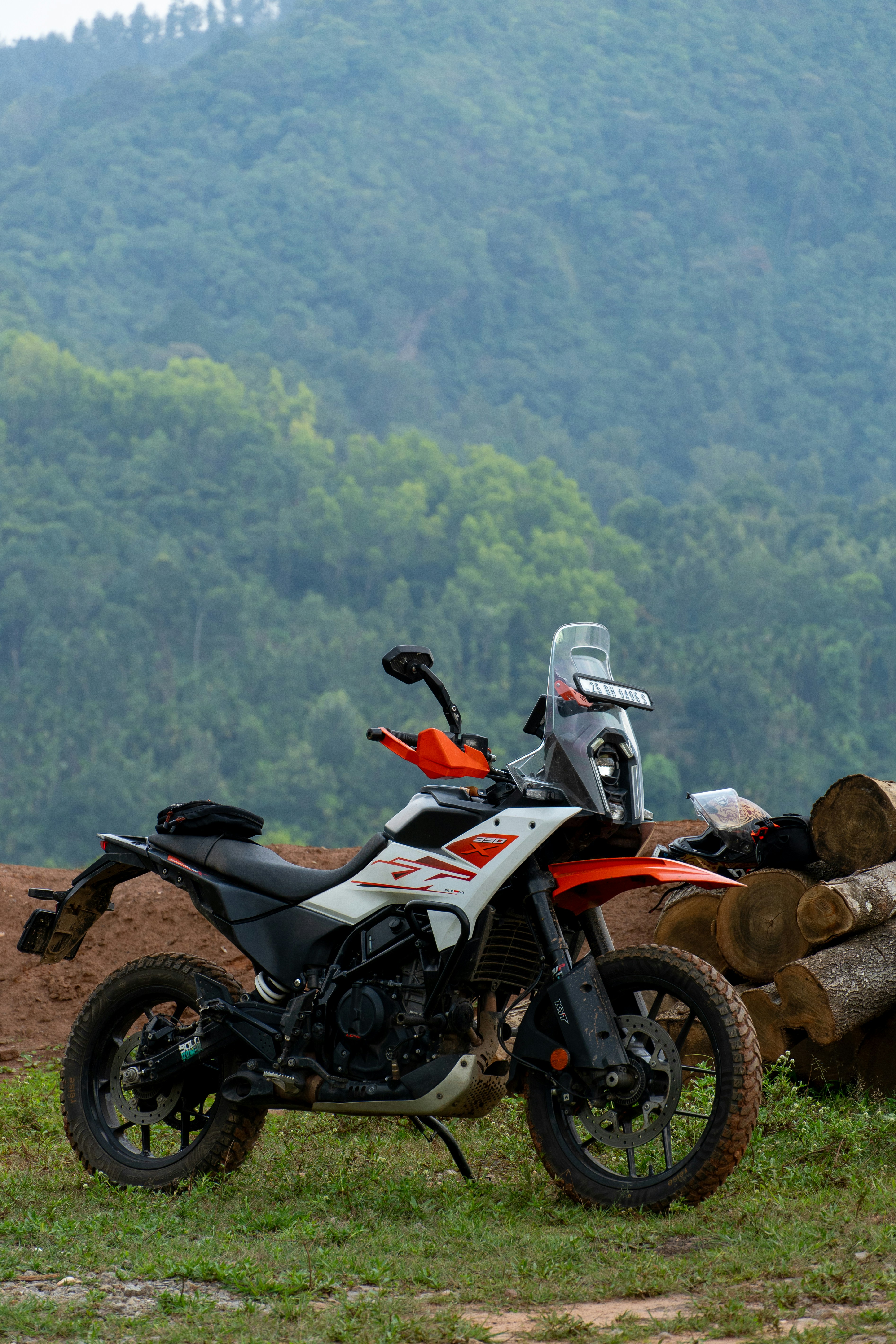 White and orange adventure motorcycle parked against green mountains.