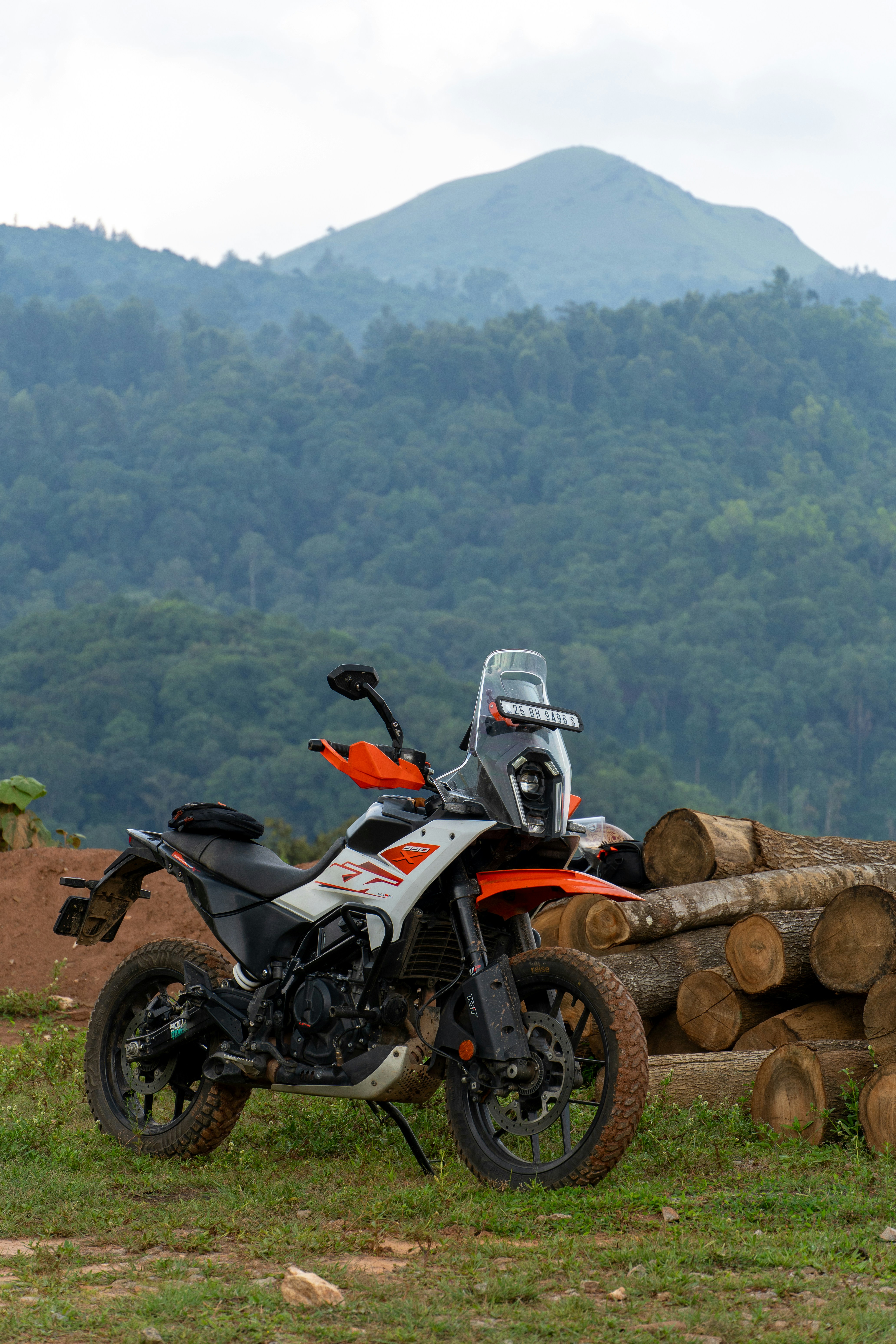 Orange Adventure: KTM Resting by Log Pile with Mountain Backdrop