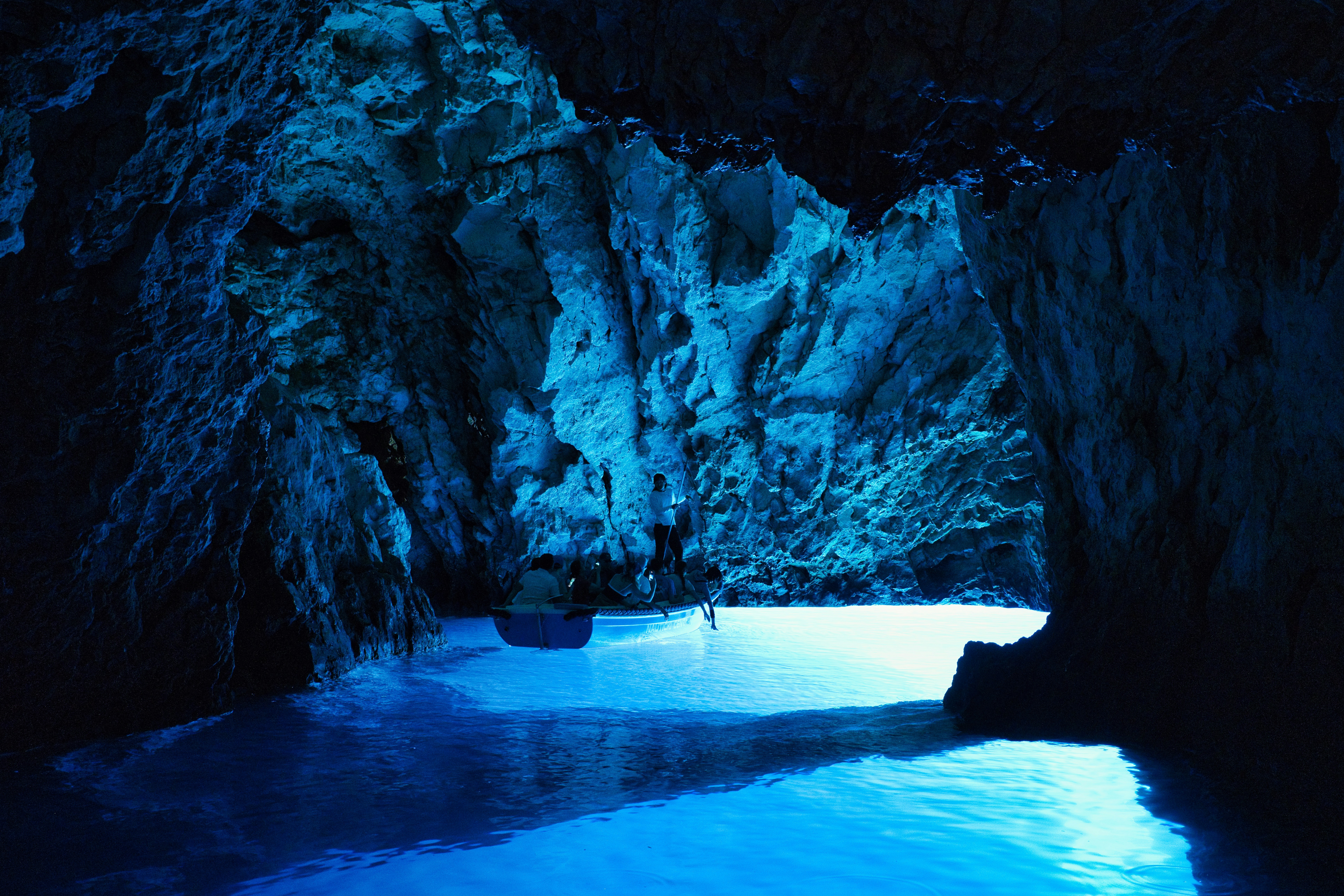 A boat on glowing blue water in a mysterious cave.
