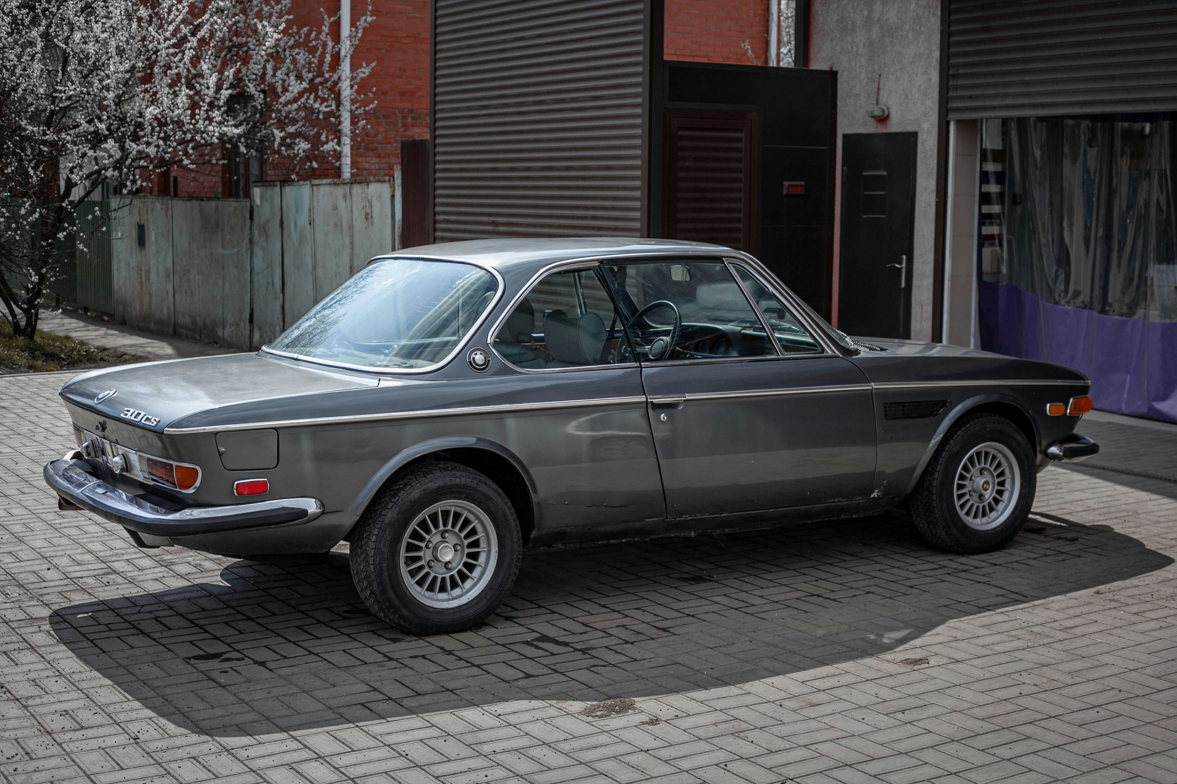 Chrome-tinged Classic: A Silver-era Mercedes-like Coupe Resting in an Urban Courtyard