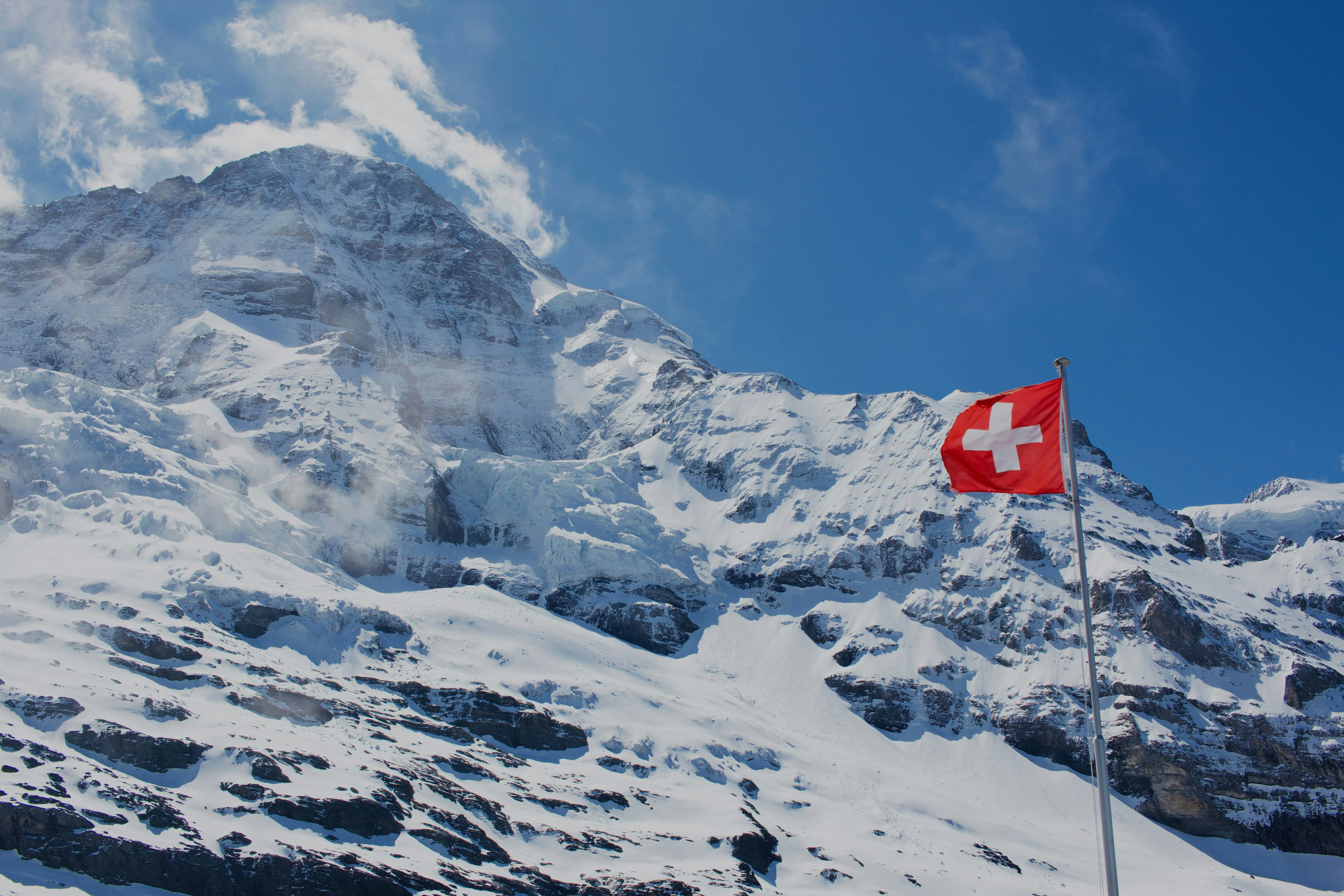 Flag on a Crest: Swiss Peak Under a Clear Blue Sky