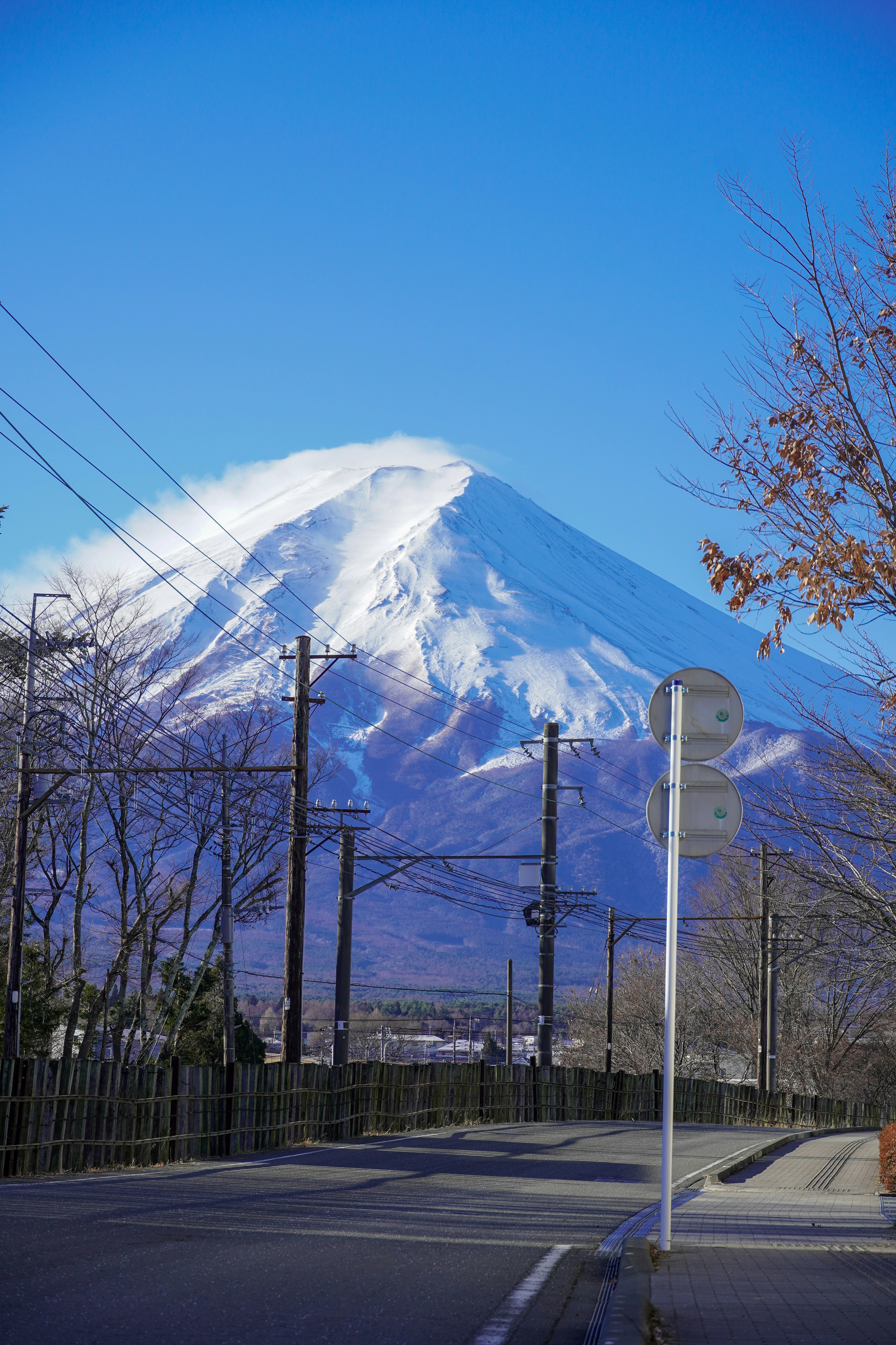 Snow-capped mount fuji with clouds and a clear blue sky.