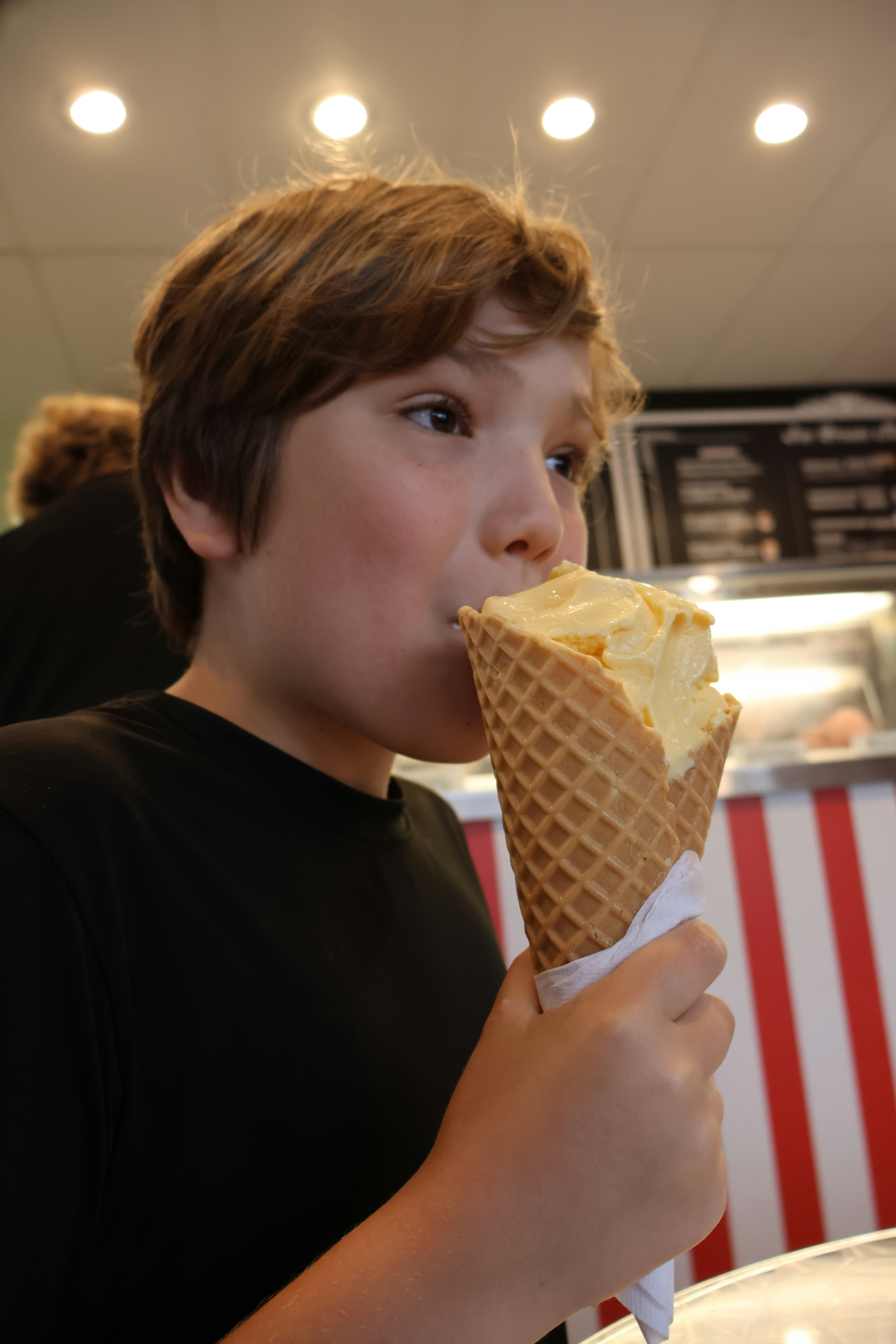 Creamy Bite: Close-up of a Young Patron Enjoying Ice Cream Cone