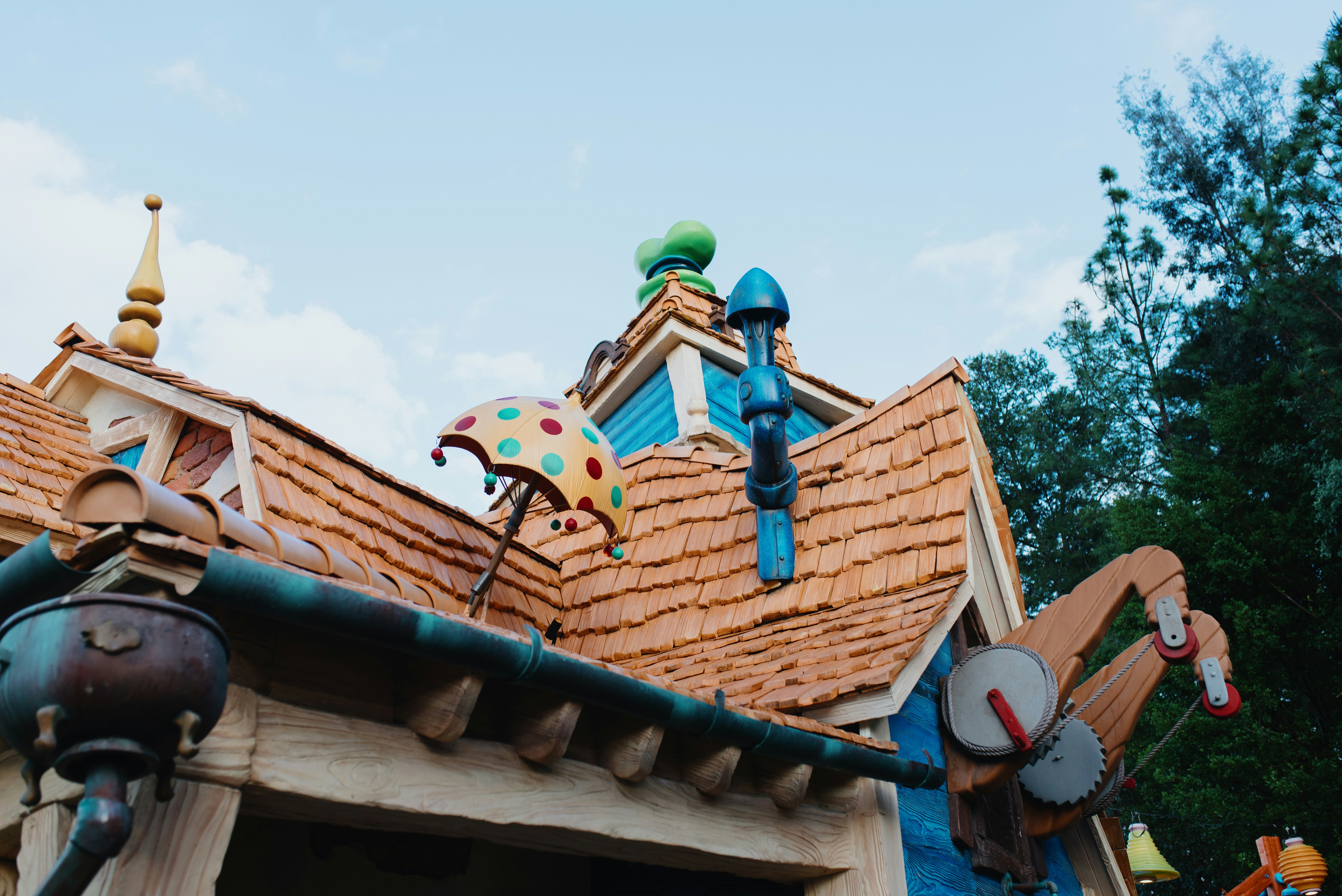 Whimsical Rooftop Parade: Painted Figures and a Polka-Dotted Umbrella Soaring Over a Toy Shop