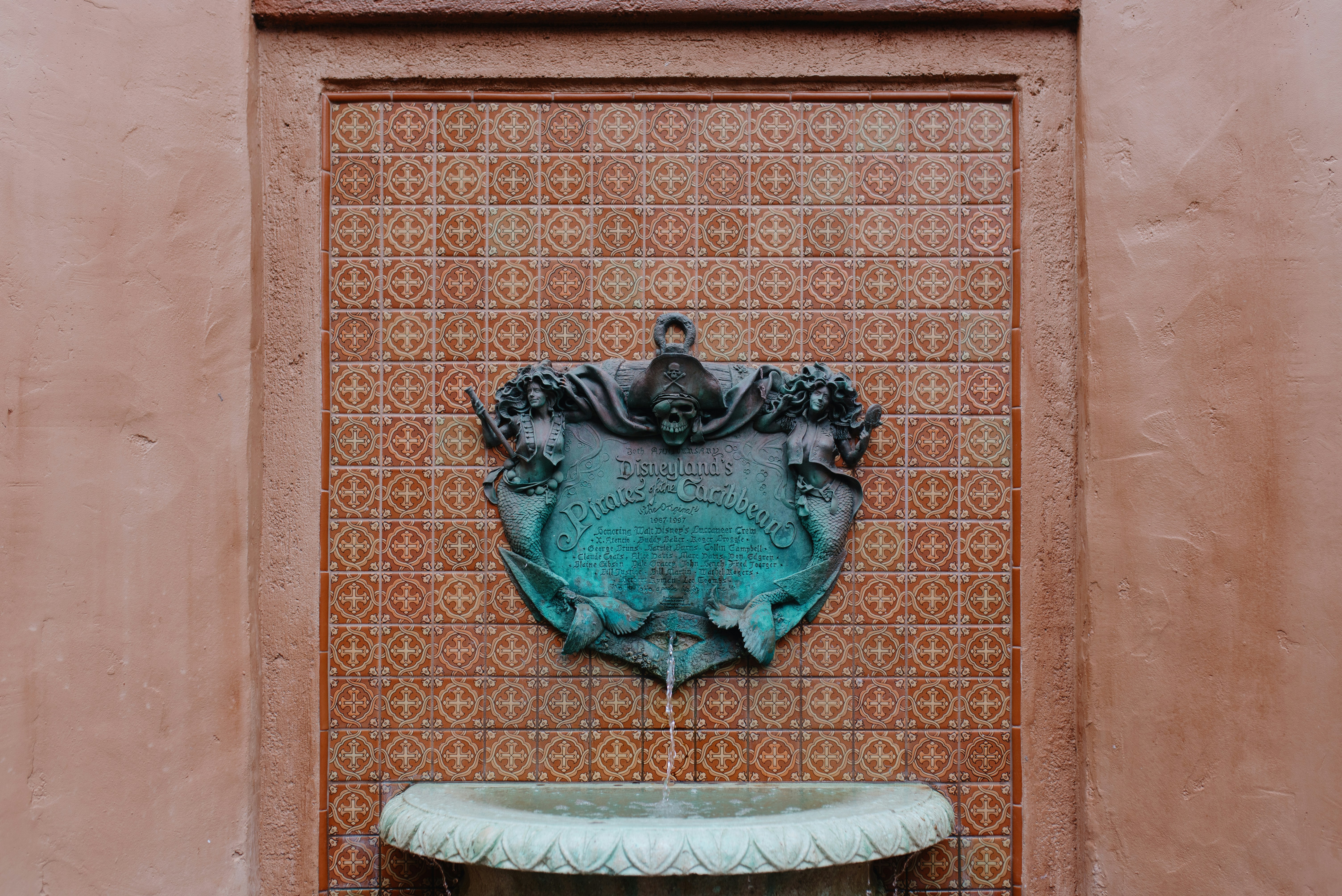 Bronze Emblem Over a Carved Tile: A Fountain Panel Framed in Terracotta