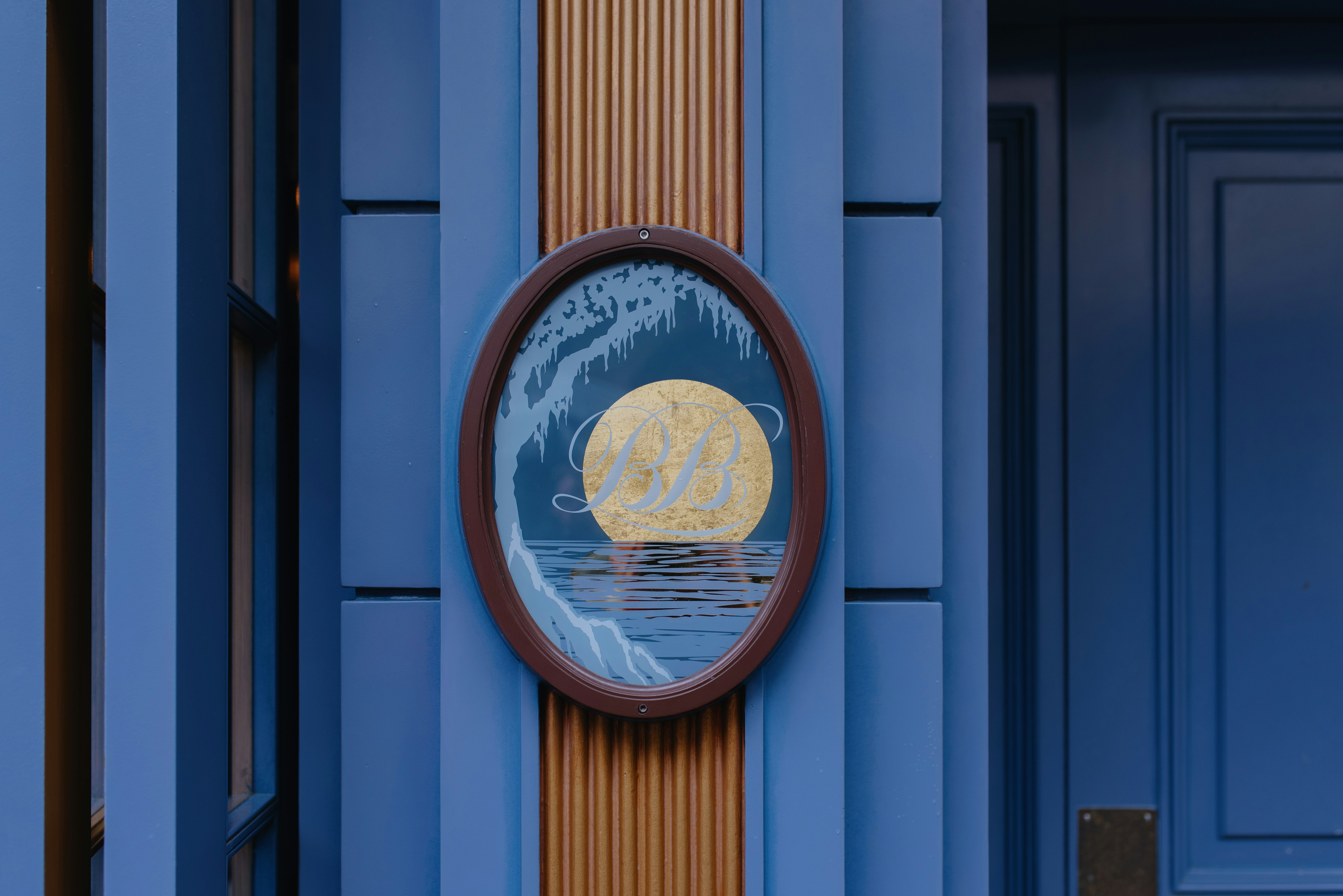 Blue Facade Circle: The Golden Script Framed by Vertical Slats