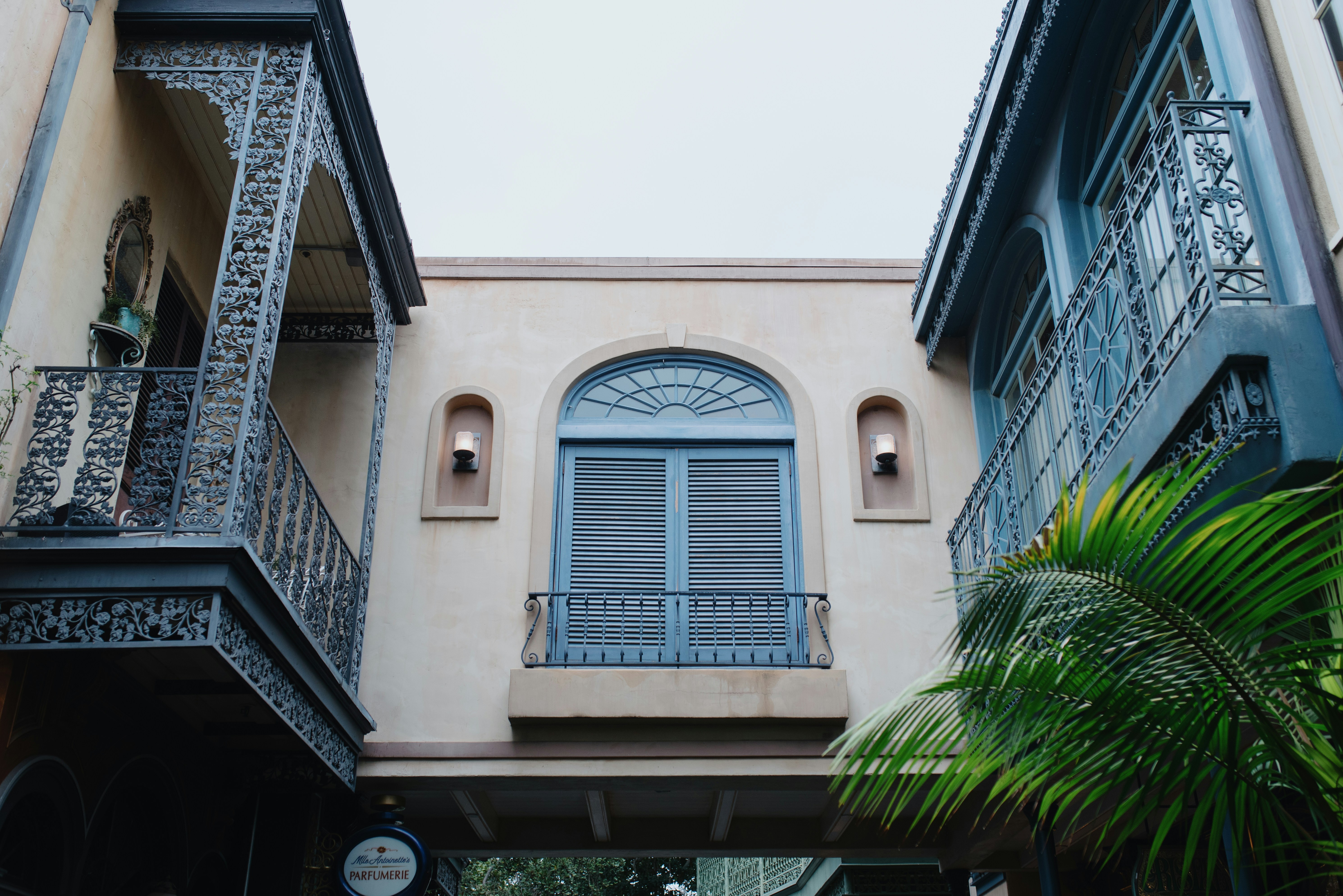 Colonial Courtyard Echoes: Arched Window Flanked by Wrought-Iron Balconies