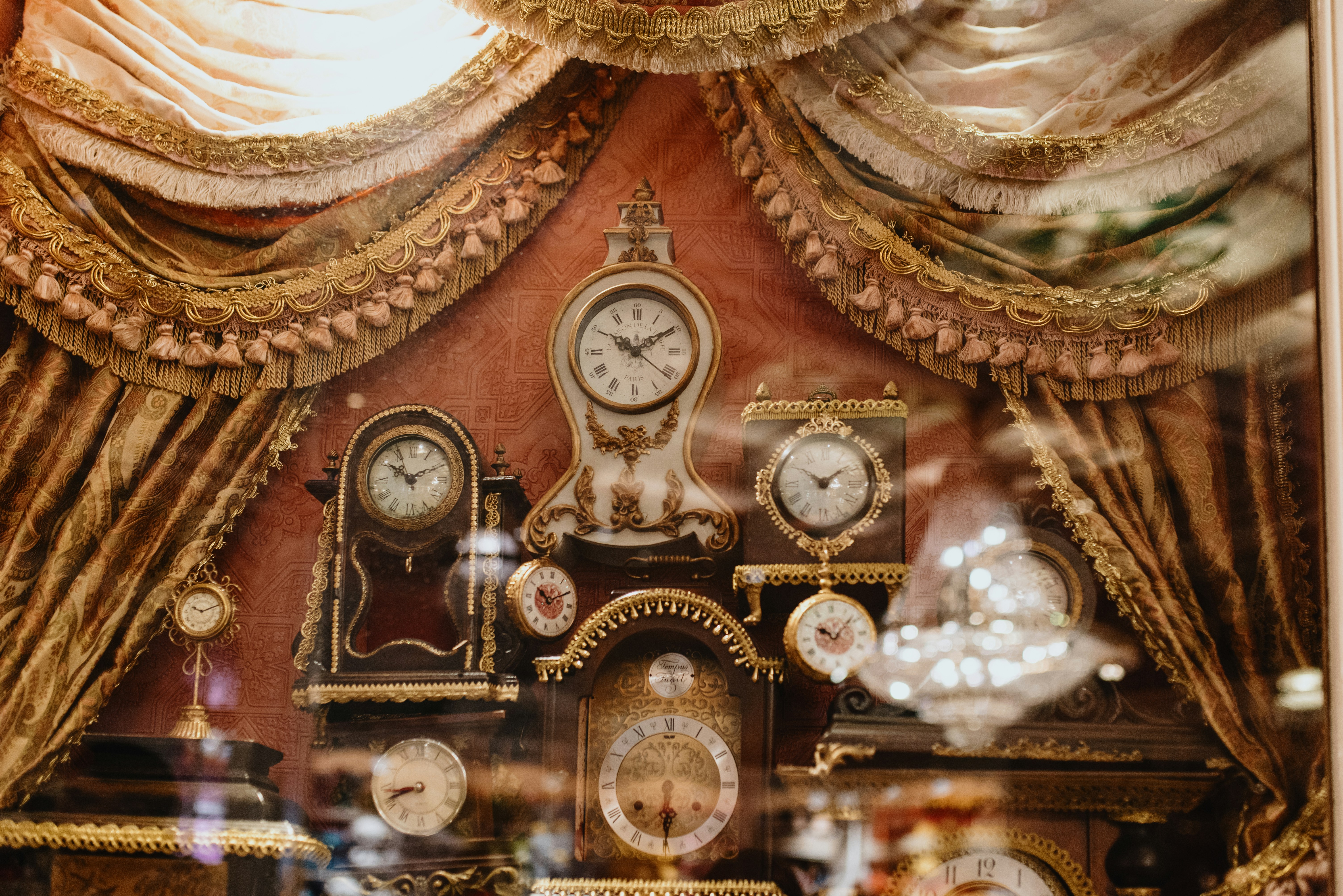 Timeless Tockery: A Display of Ornate Clocks Behind Velvet Drapery