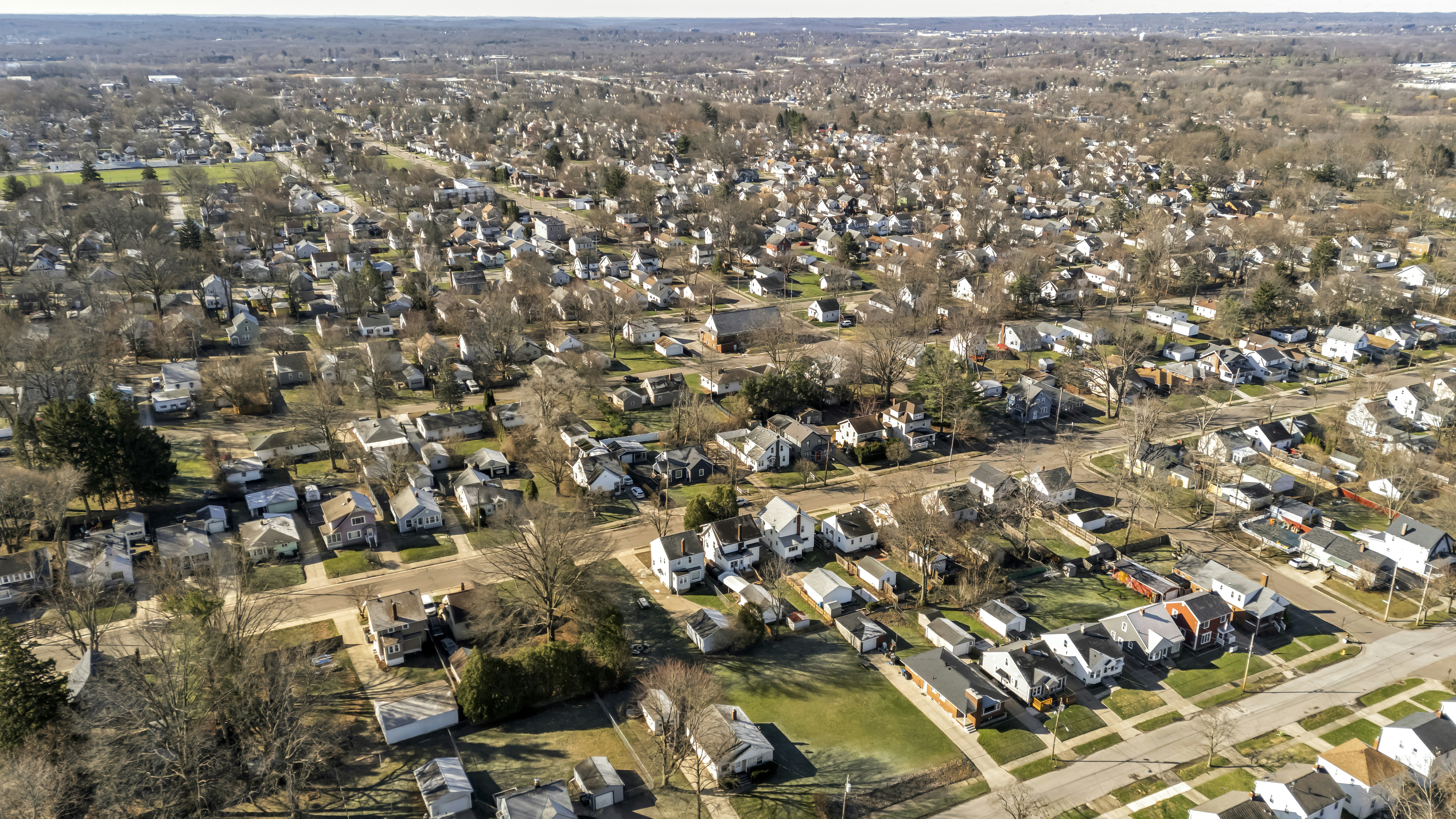 Drone shot of a mid west suburb, with colonial homes checkered up and down the street in the winter