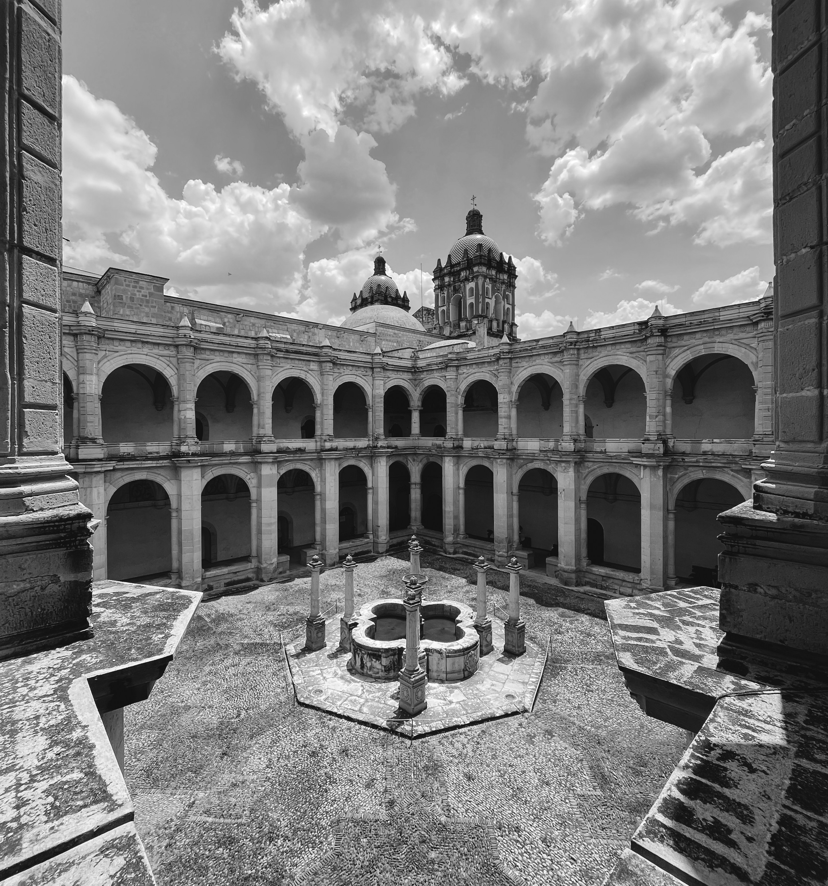 Historic architectural courtyard with arches, central fountain, and domes.